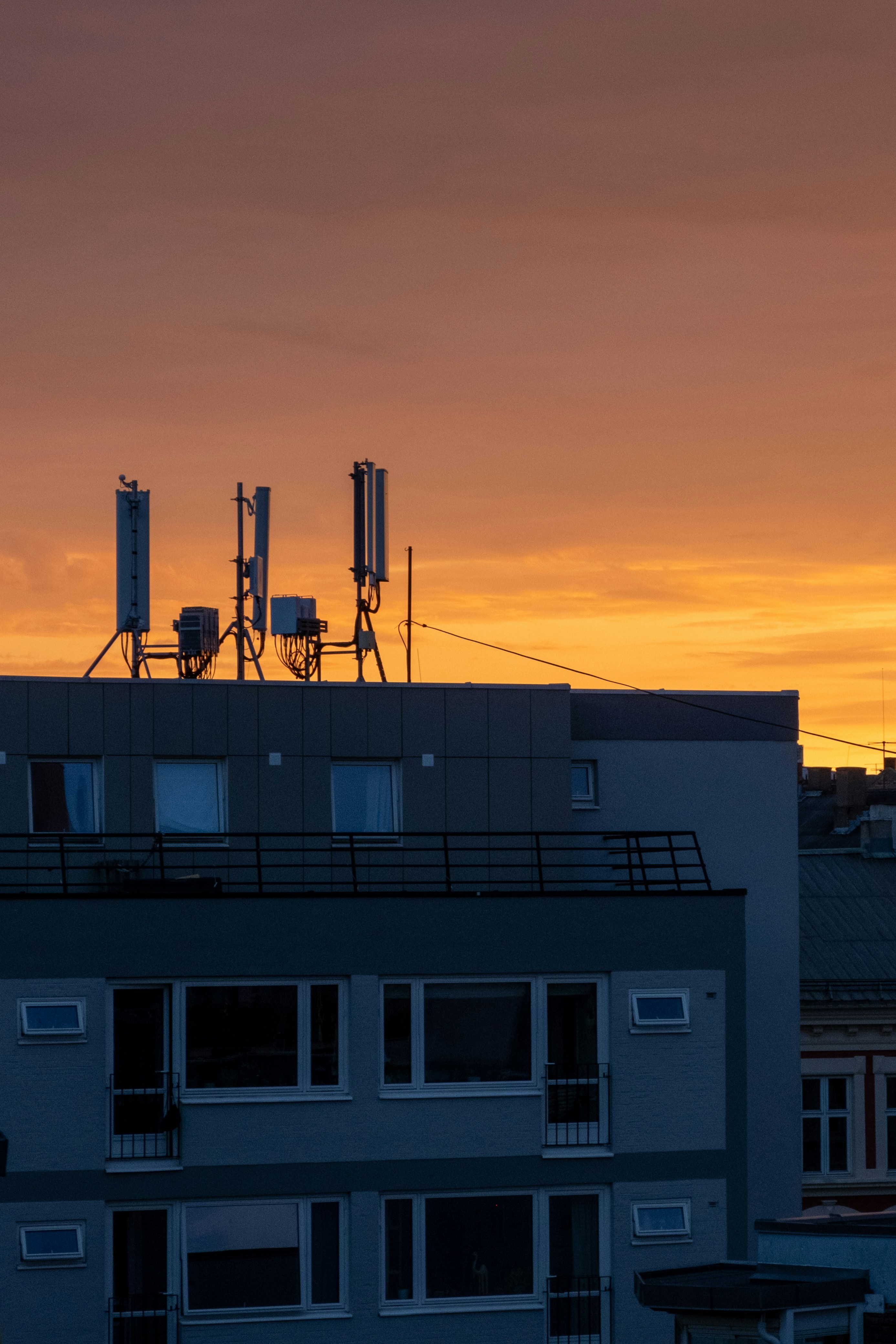 Dusk Over the Rooftop: Antennas Against a Tangerine Sky