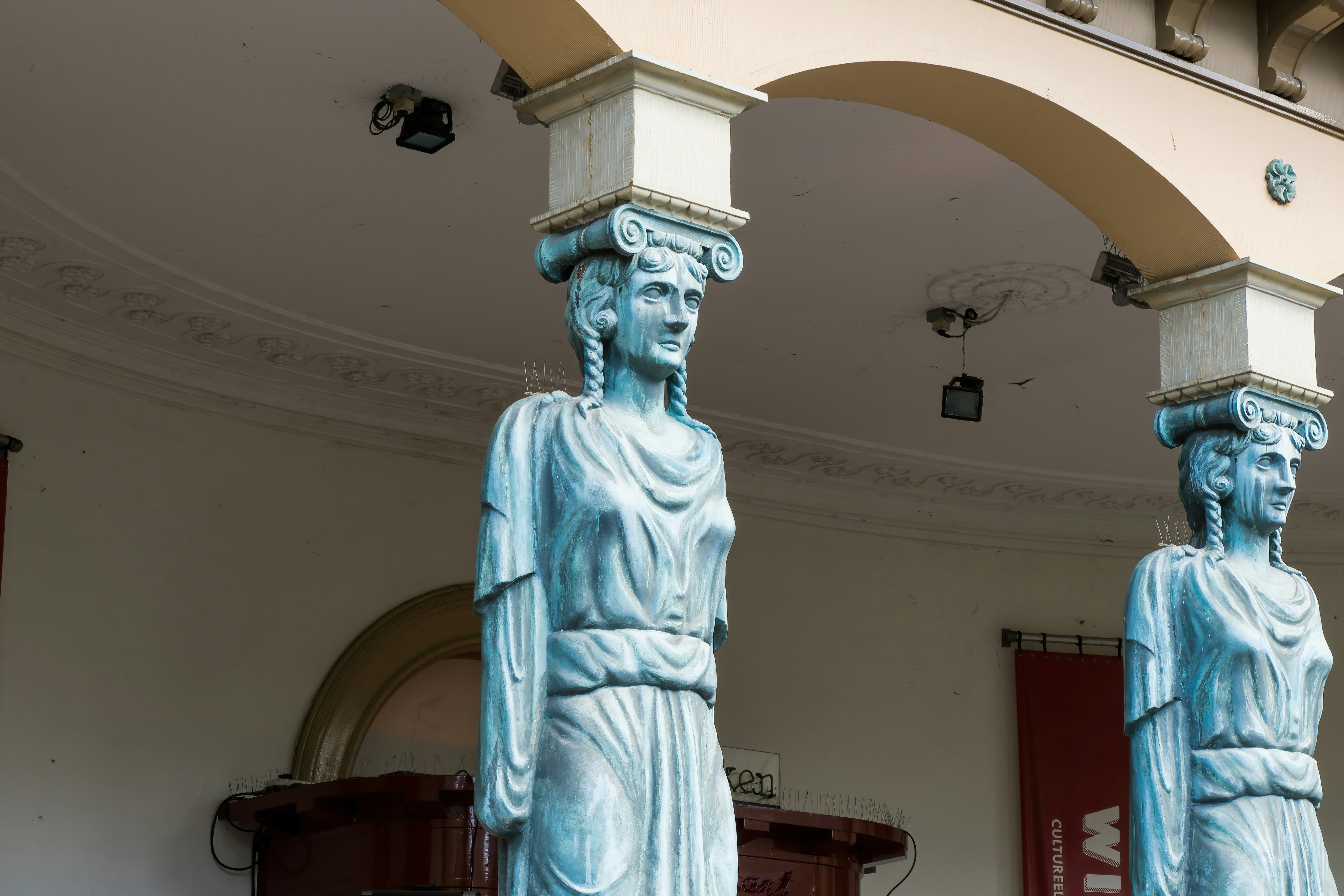 Cerulean Gatekeepers: Twin Statue Sentinels Under a Colonial Arcade