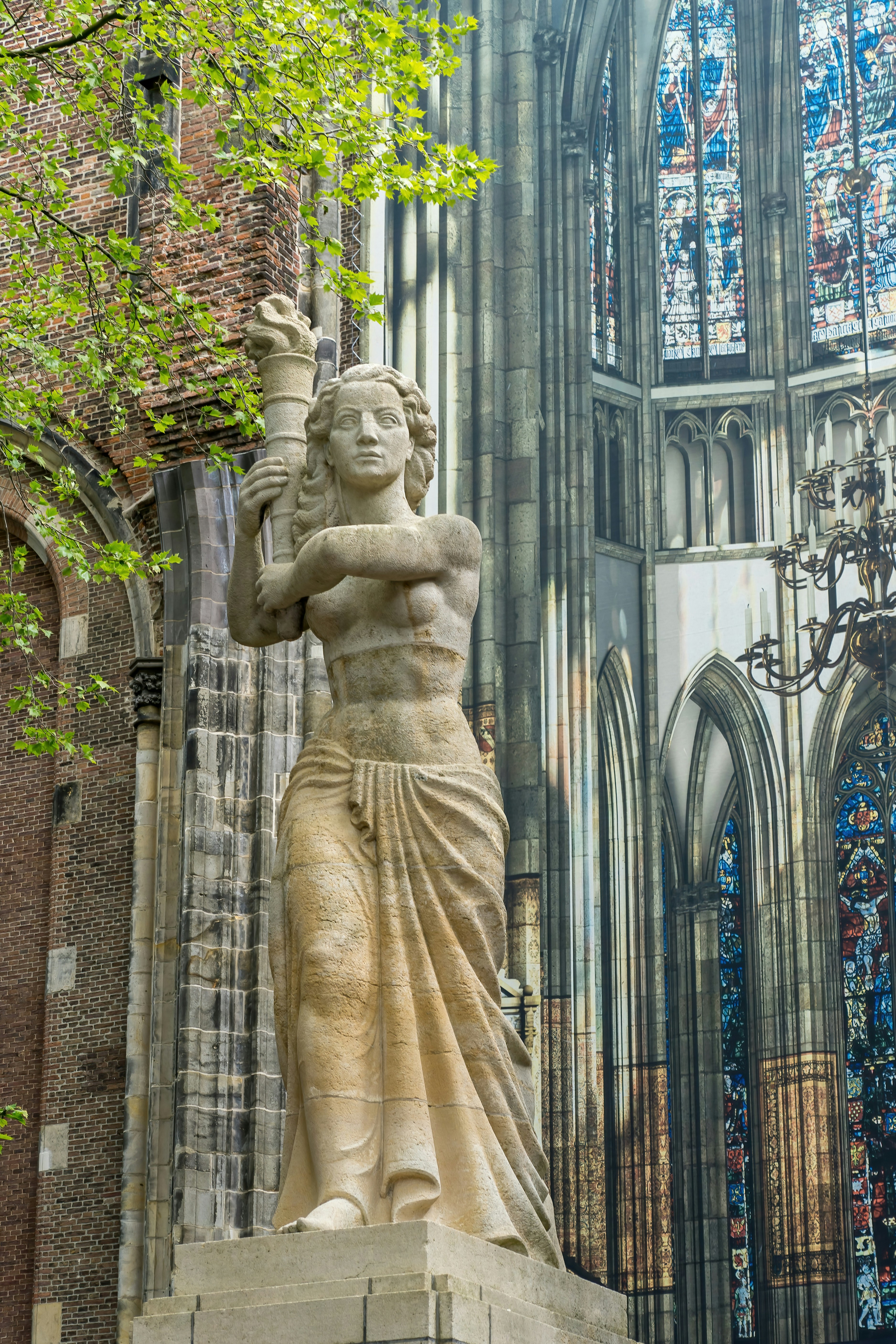 Stone Sentinel in Gothic Light: A Draped Figure Framed by Cathedral Glass
