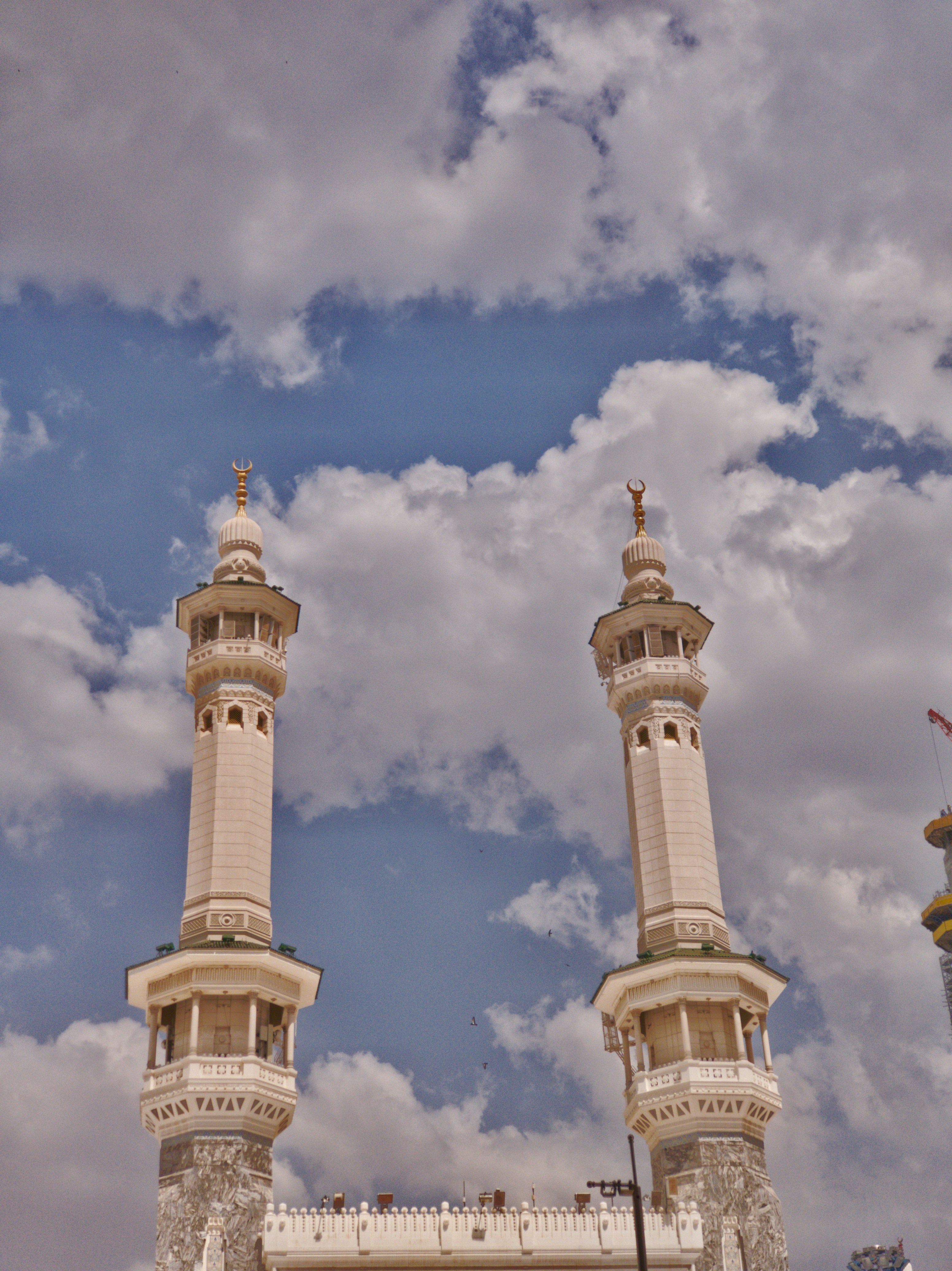 Two tall white towers against a cloudy blue sky photo – Free Mosques ...
