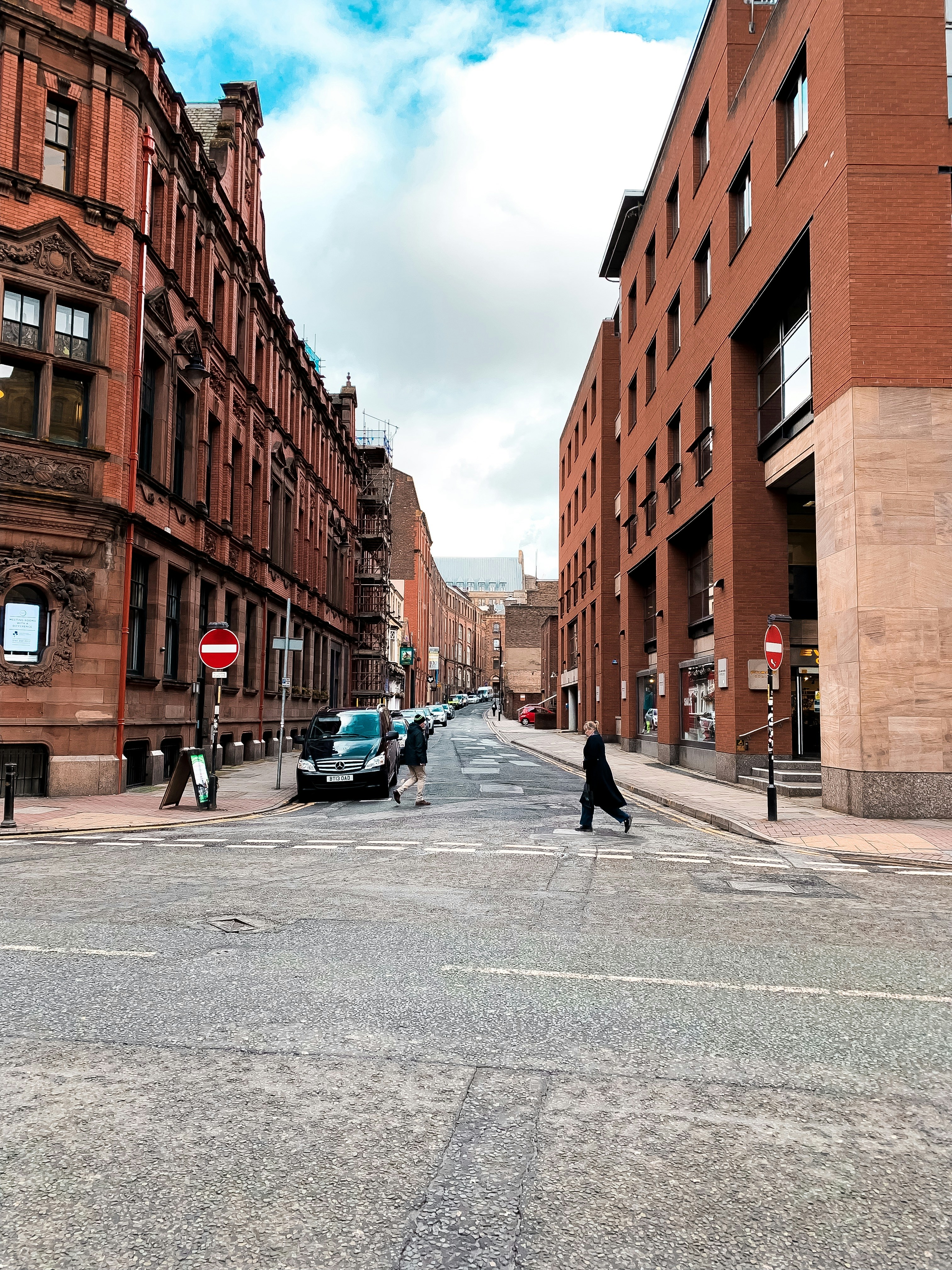 Manchester street with people walking | a person standing in the middle of an empty street