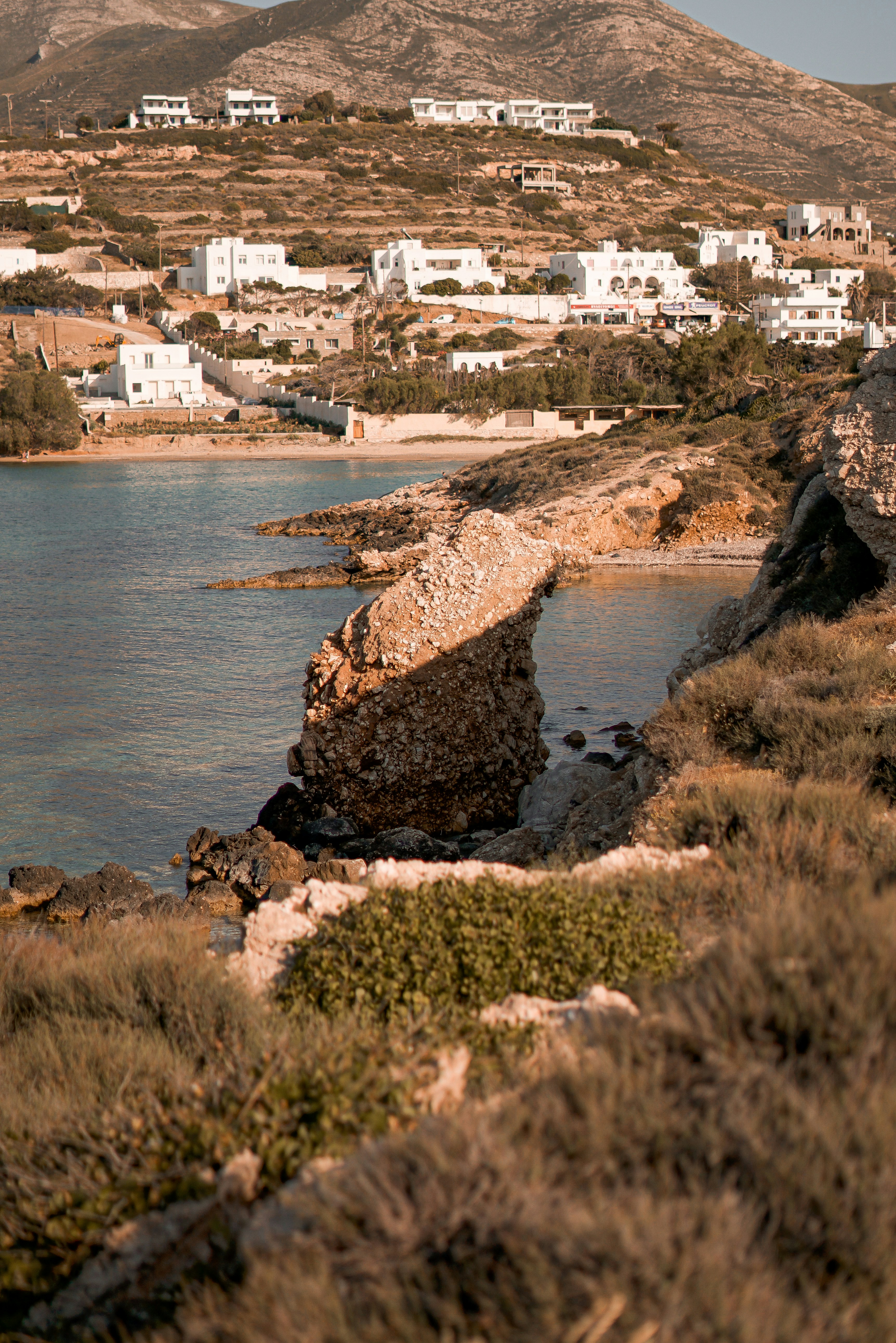 Sunlit White-Washed Village Framed by a Rugged Cove and Sea Rocks