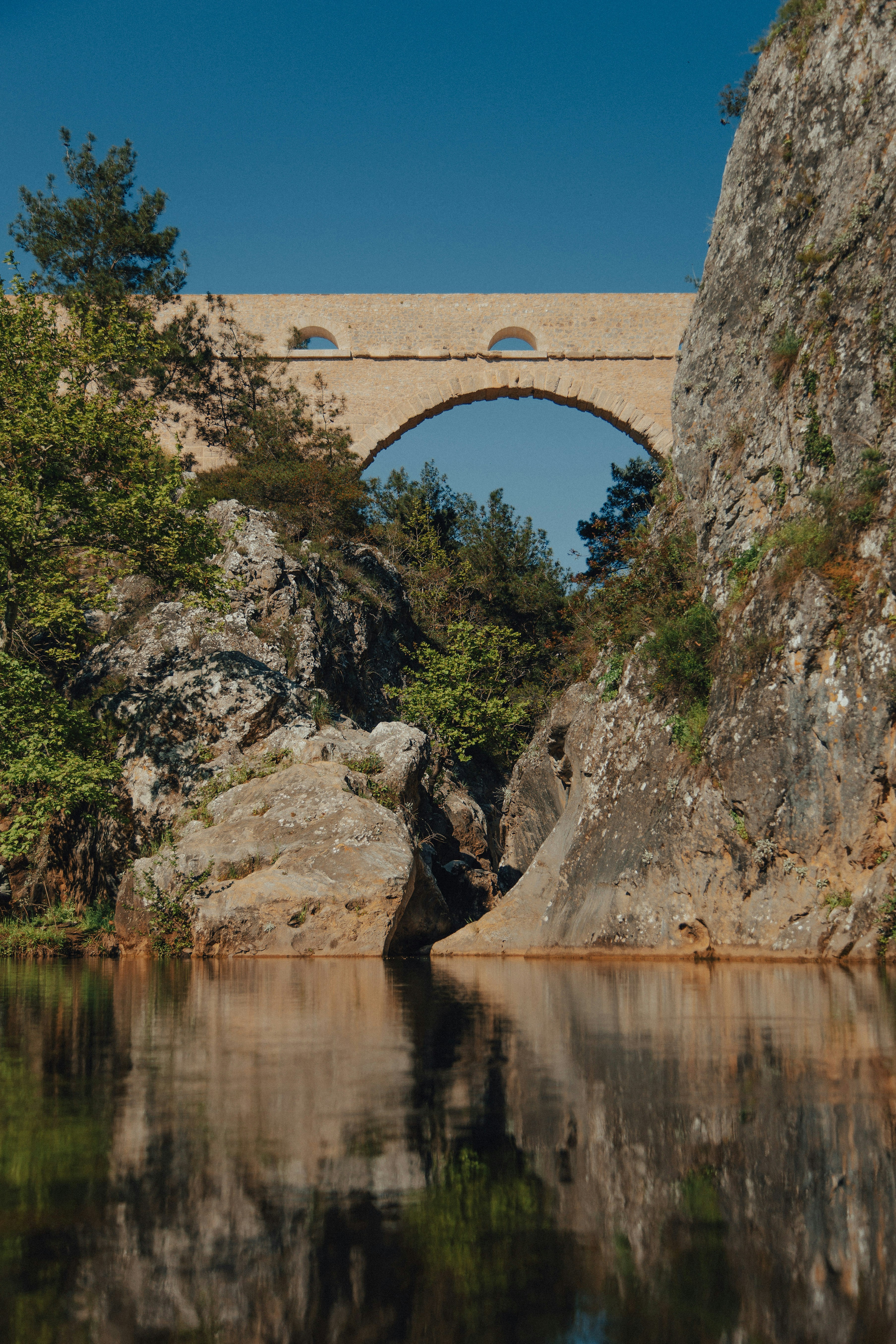 A bridge over a body of water surrounded by rocks photo – Free Rock ...
