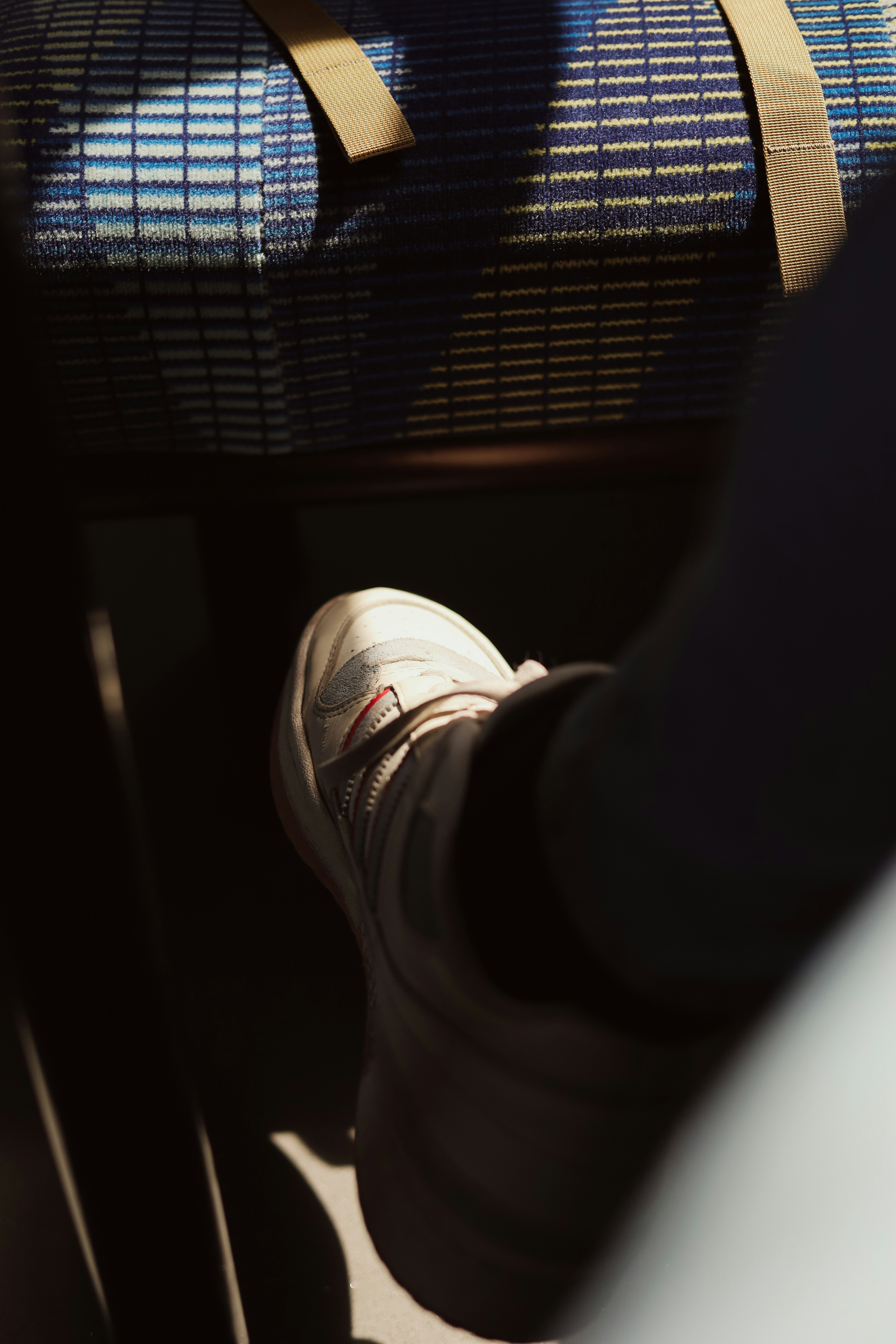 White Sneaker in Dim Bus Light Against Blue Plaid Cushions
