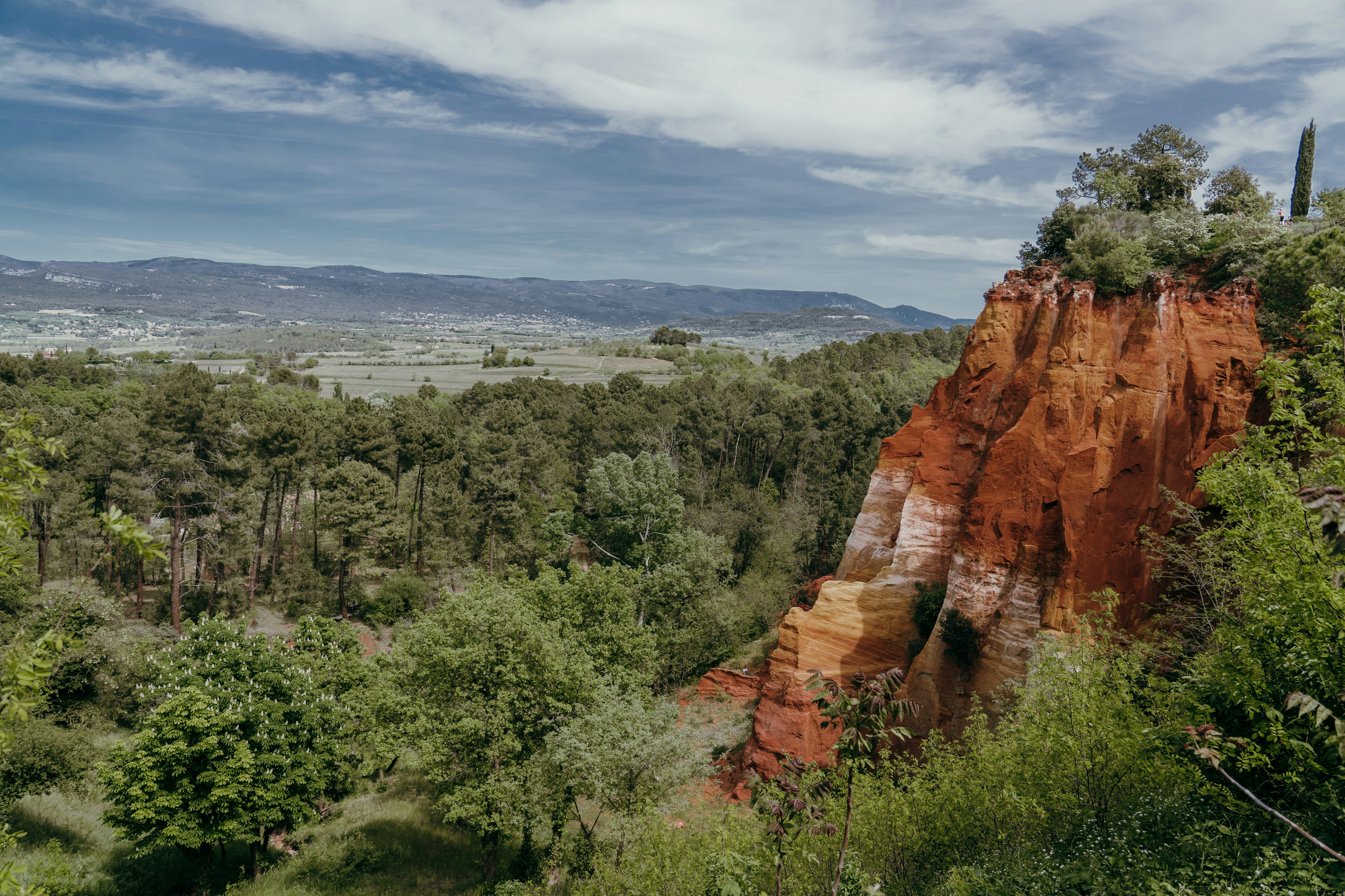 Crimson Strata Framing a Verdant Valley Under a Wide Sky