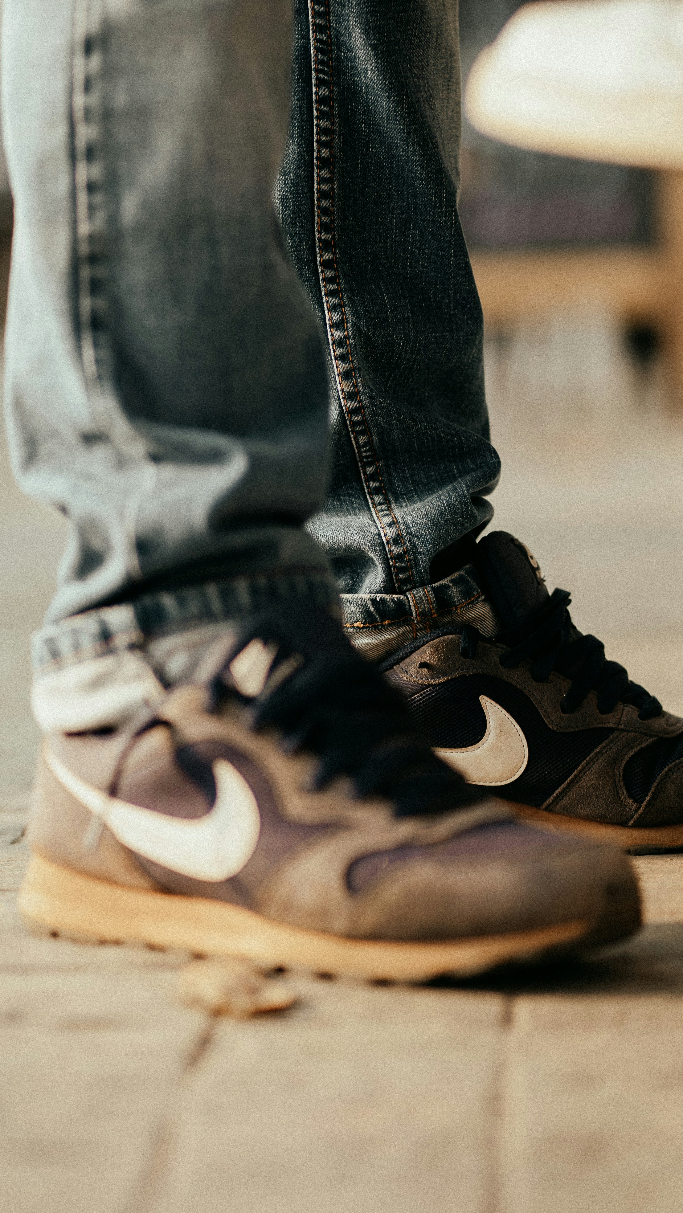 Swoosh on the Sole: A Close-Up of Sneakers Resting on Weathered Wood