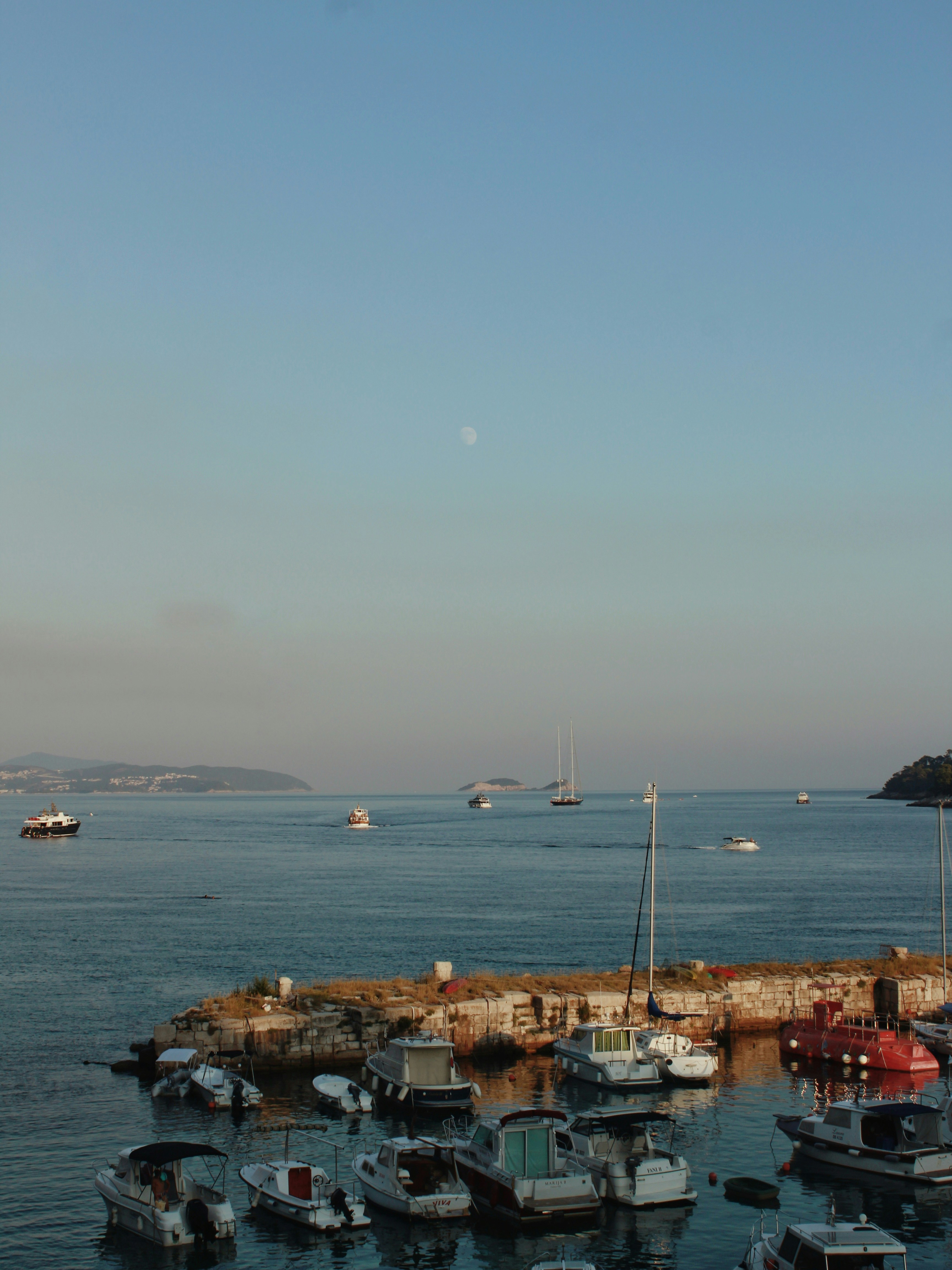 Harbor Mosaic: Boats Rest Along a Stone Pier Under a Quiet Sky