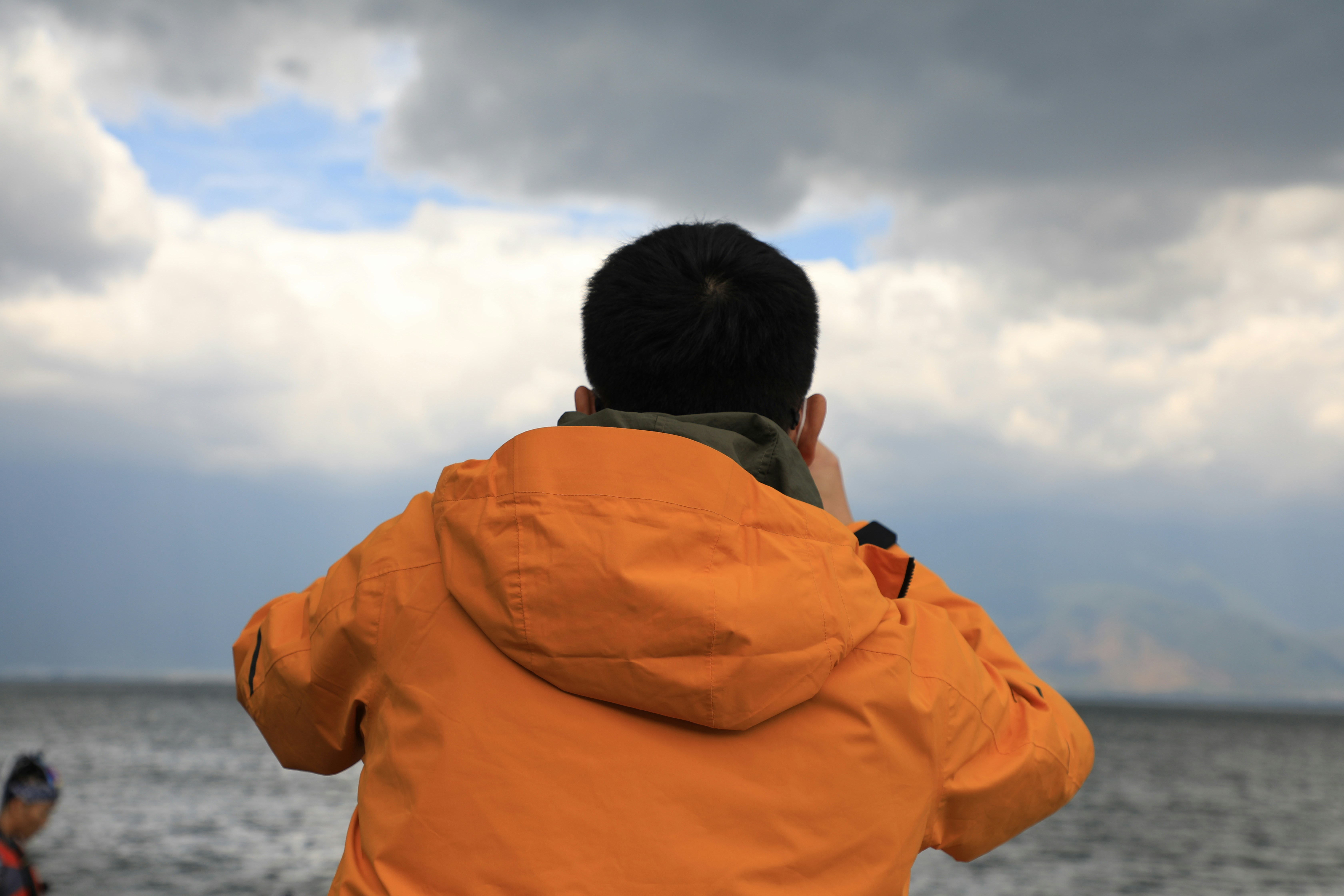 Orange Jacket, Quiet Horizon: A Back-Turned Photographer Capturing the Lake