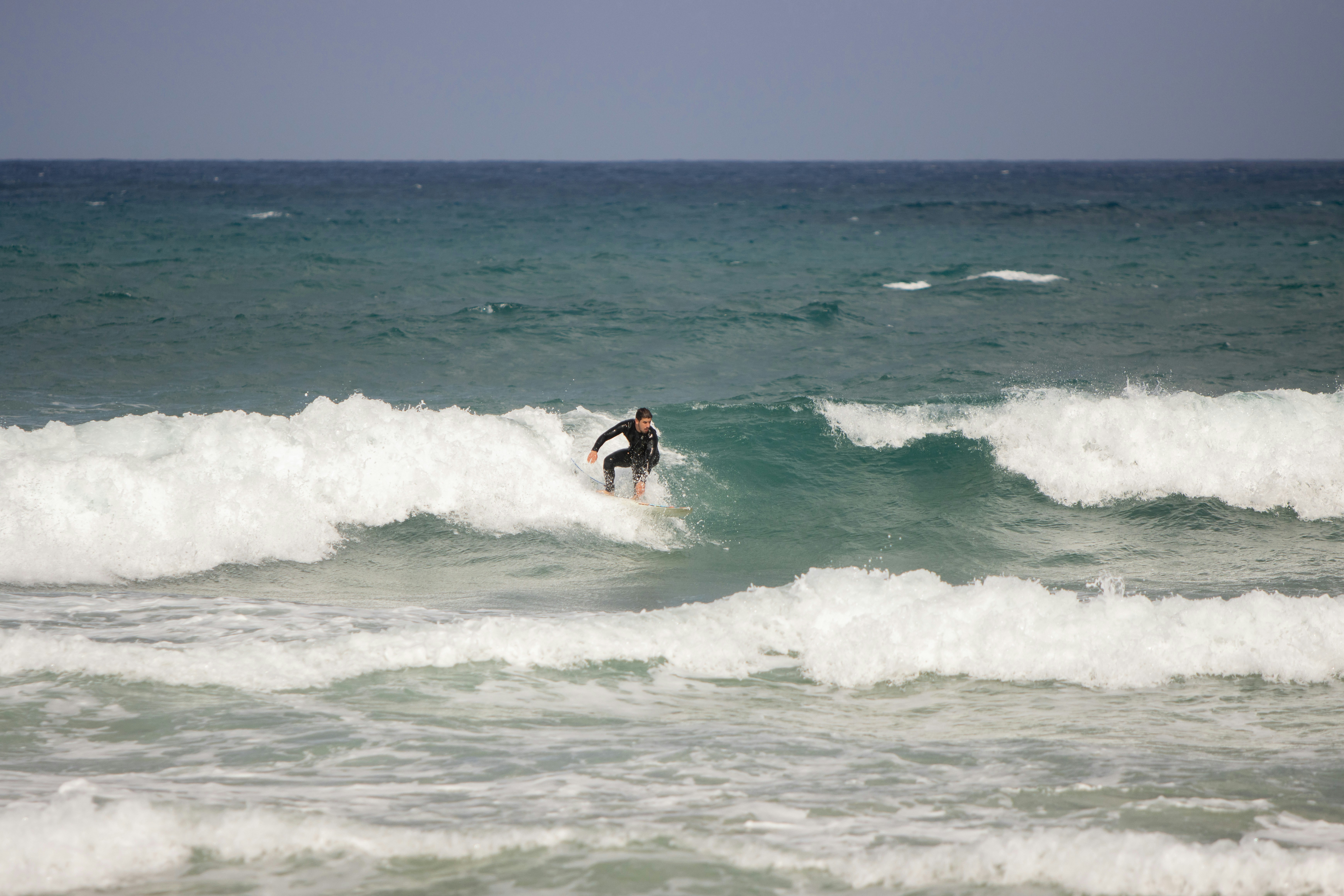 Turquoise Crest: Lone Surfer Carves Through a Coastal Break