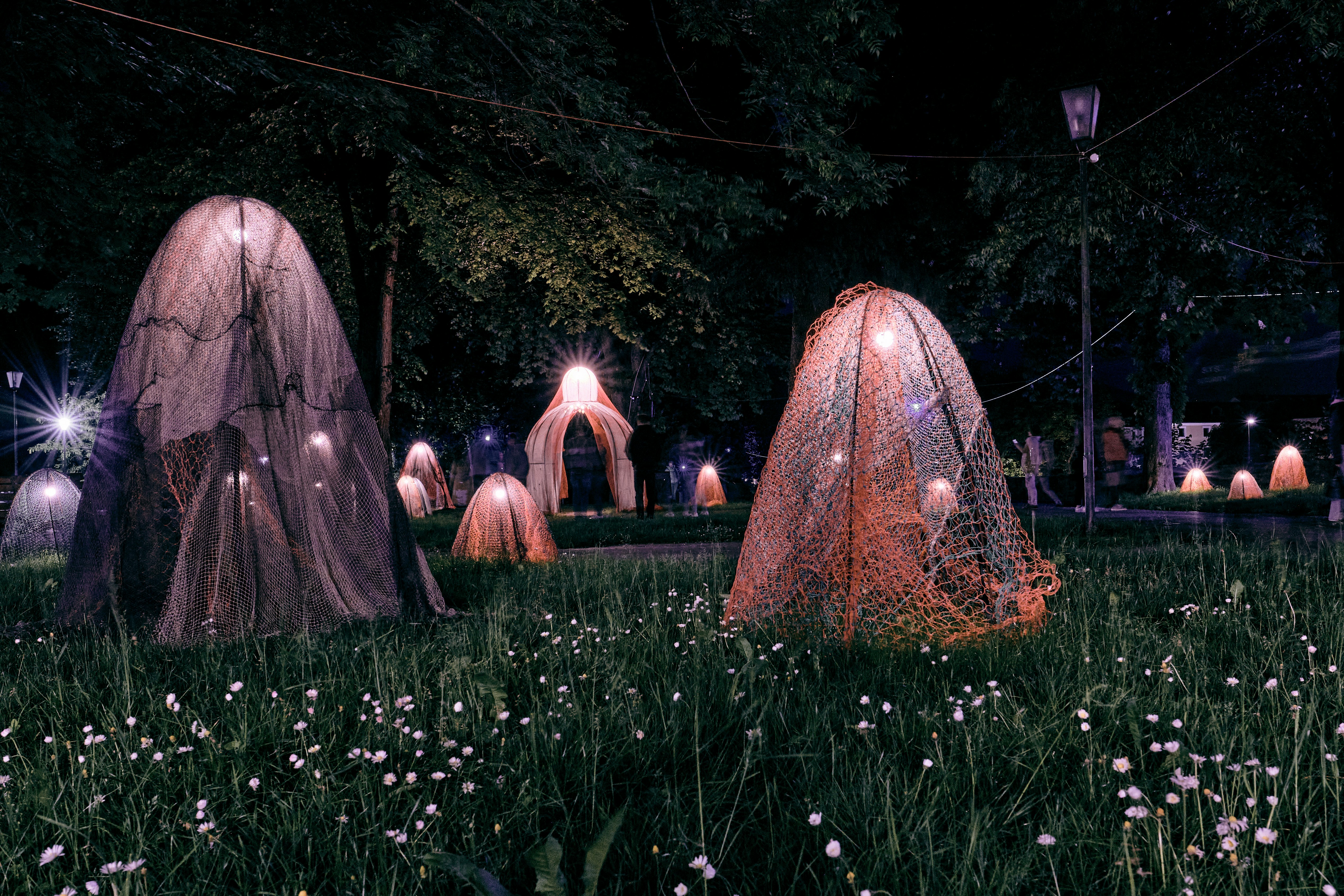 Glownet Lanterns in a Moonlit Meadow: Netted Huts Radiating Warm Light
