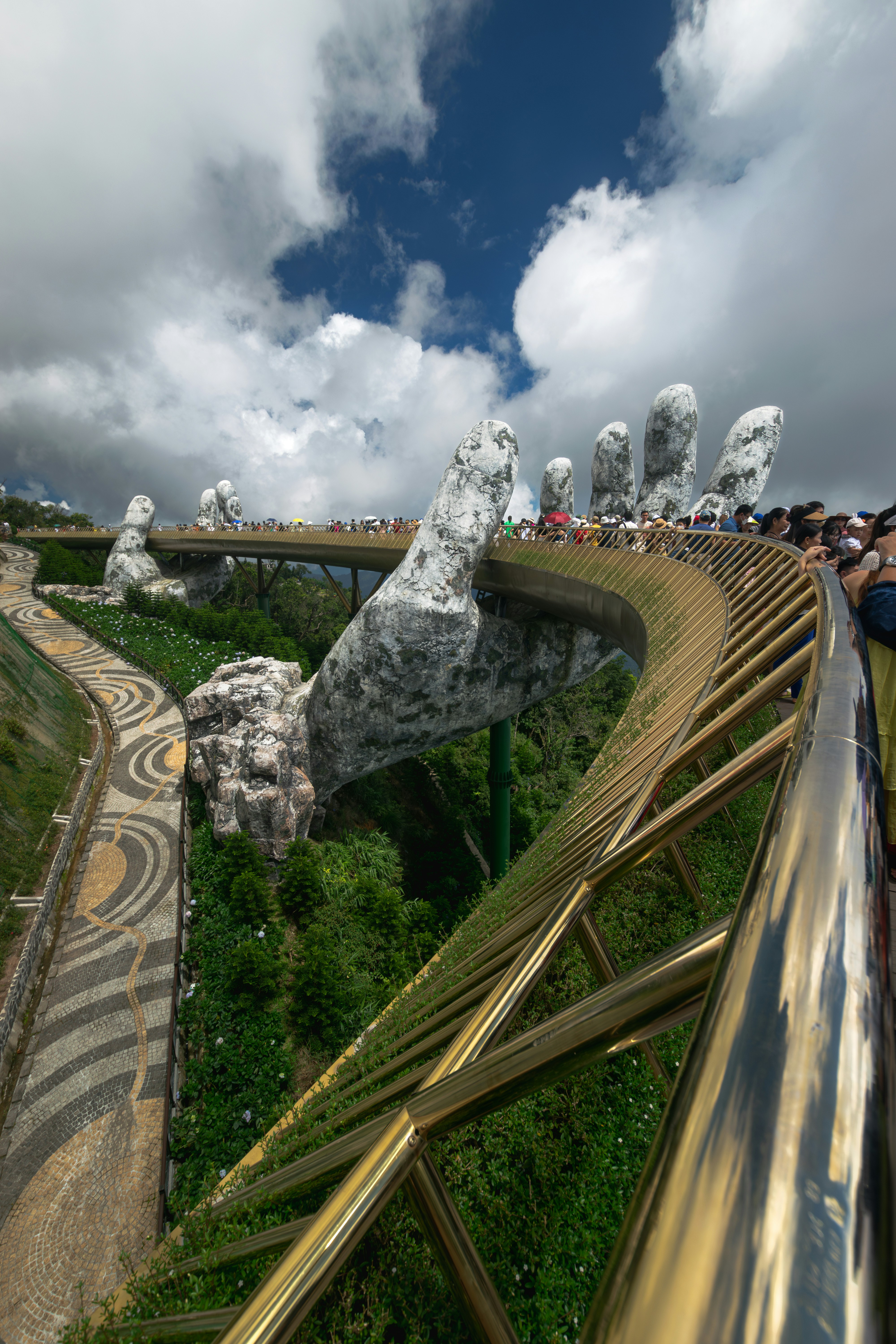 Wide angle leading line view of the Golden Bridge, Ba Na Hills. Cloudy day. Picture taken with the outer look of the handrail. Da Nang, Vietnam, Aug/22. | a view of a roller coaster in a park