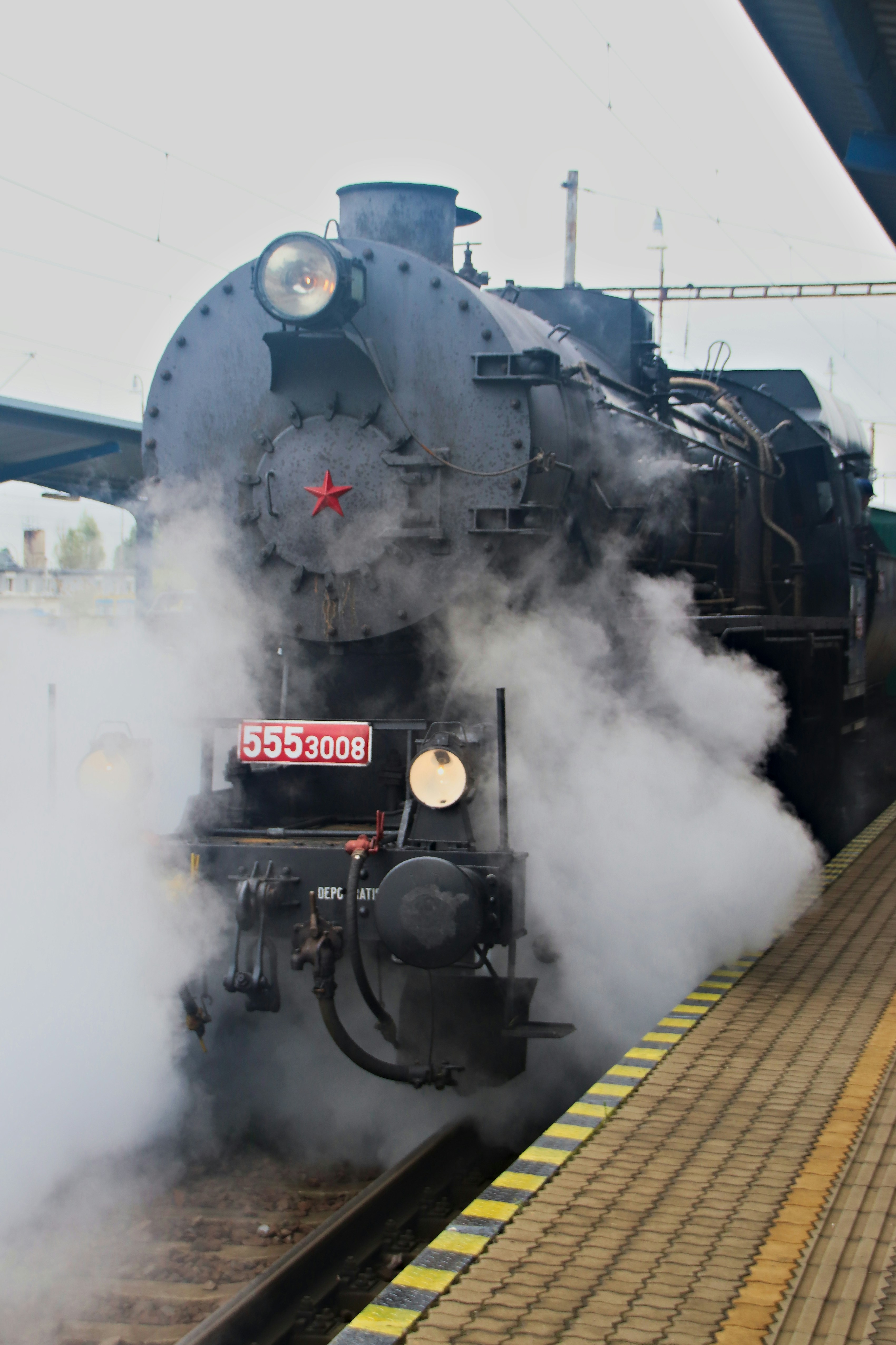 A steam engine train pulling into a train station photo – Free ...