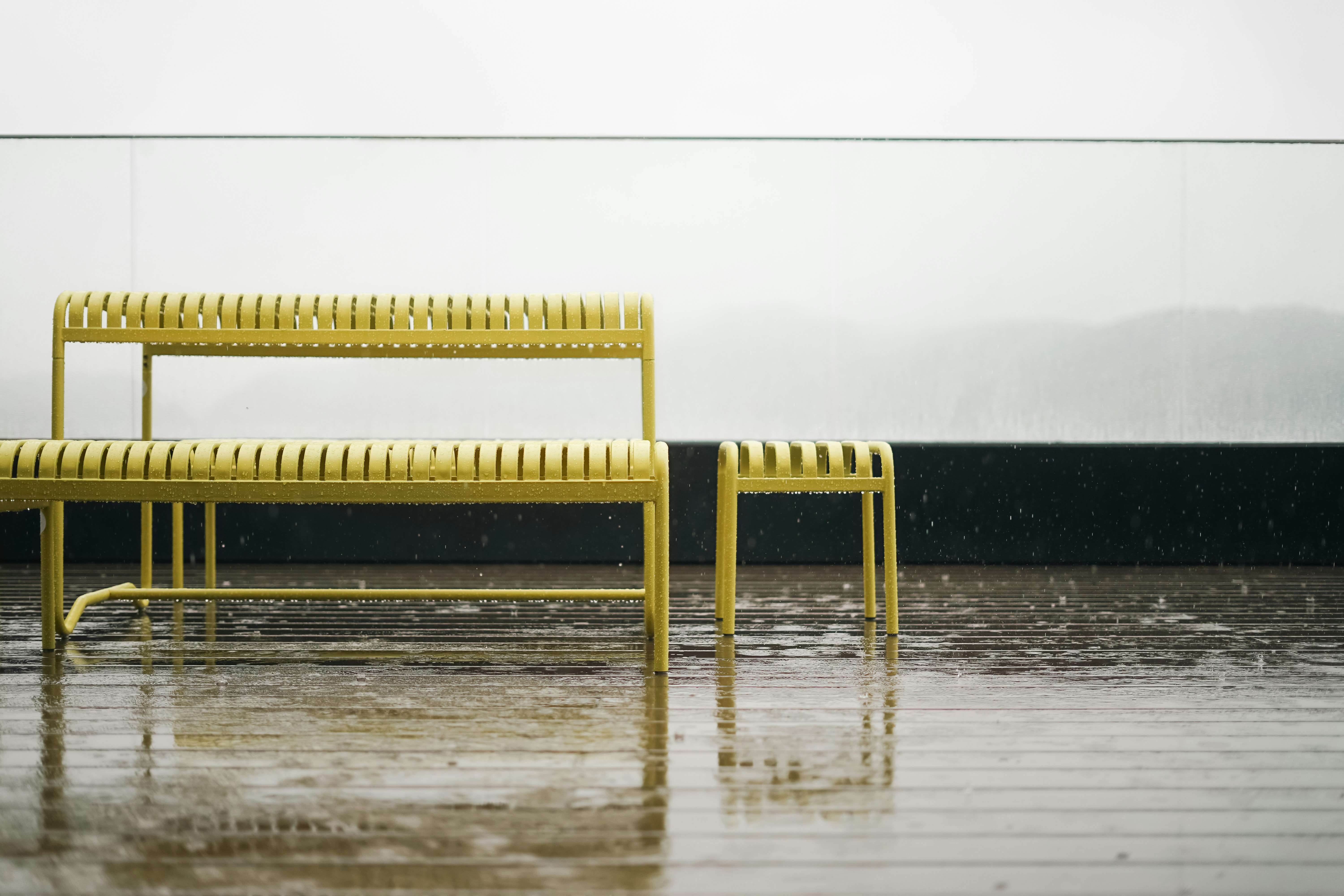 A couple of yellow benches sitting on top of a wet floor photo – Free ...