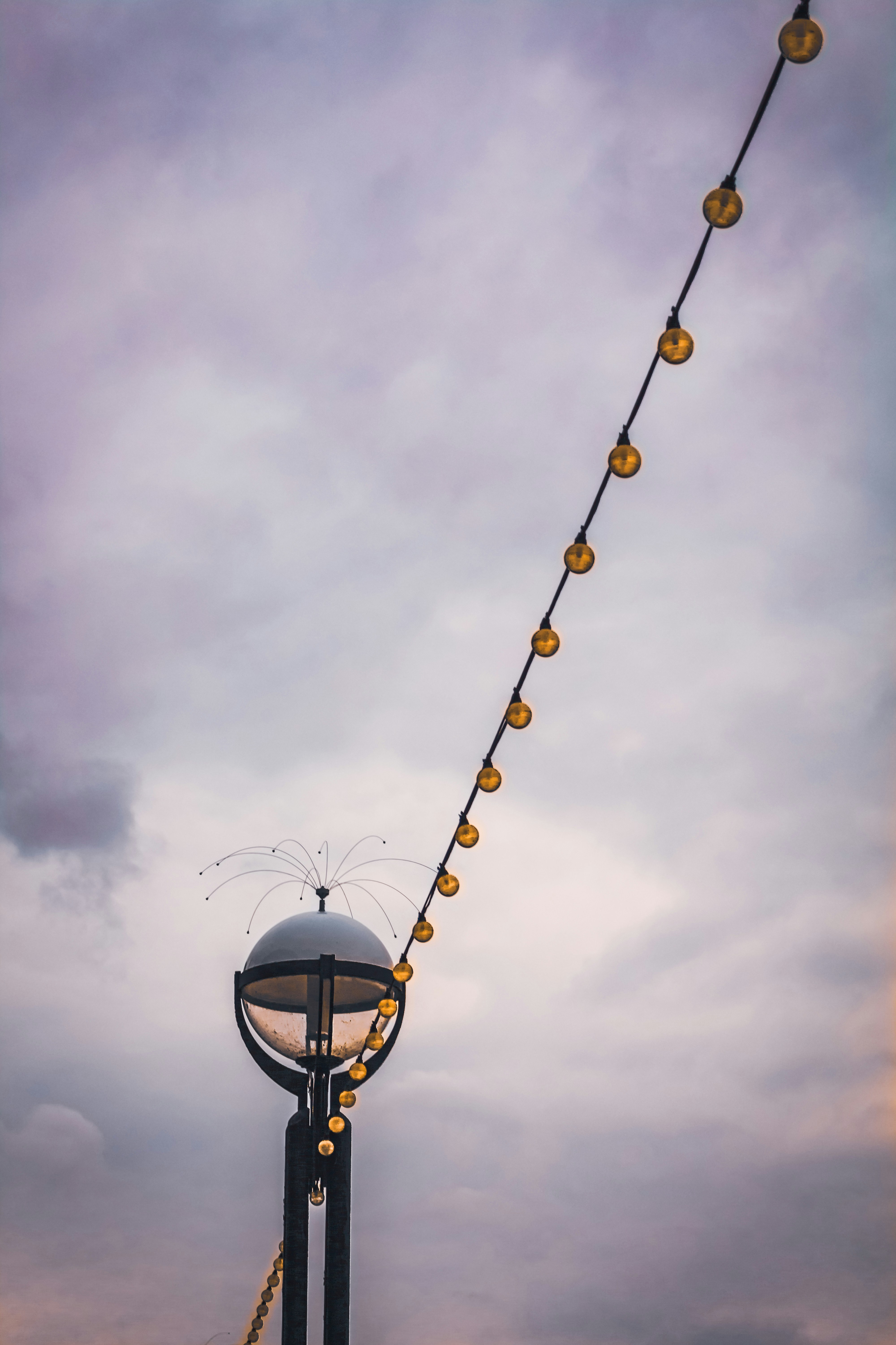 Arc of Amber Orbs: A Streetlamp Serenade Across a Cloudy Sky