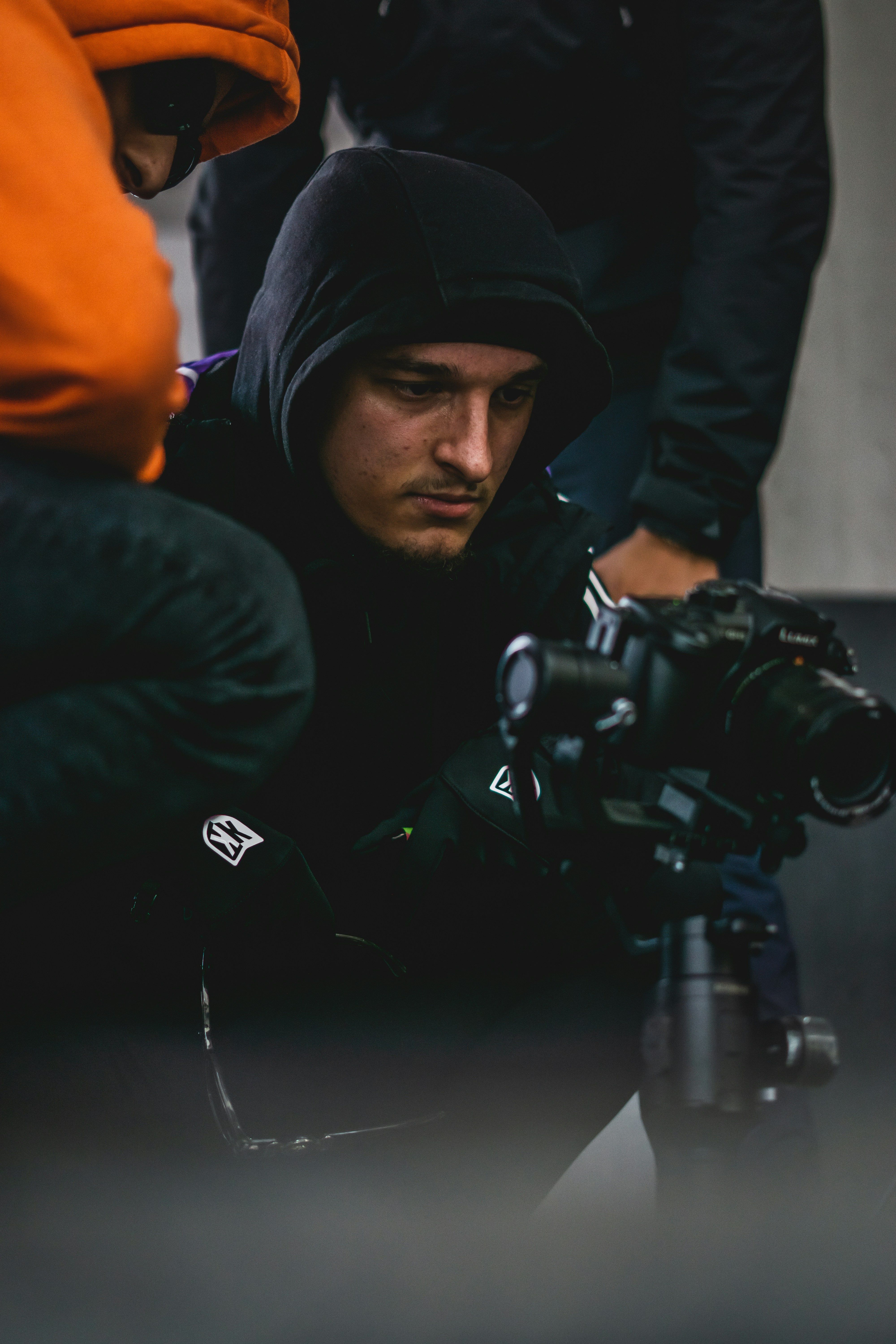 Dark Focus: Hooded Operator Calibrates a Cinematic Rig Amid Quiet Tension