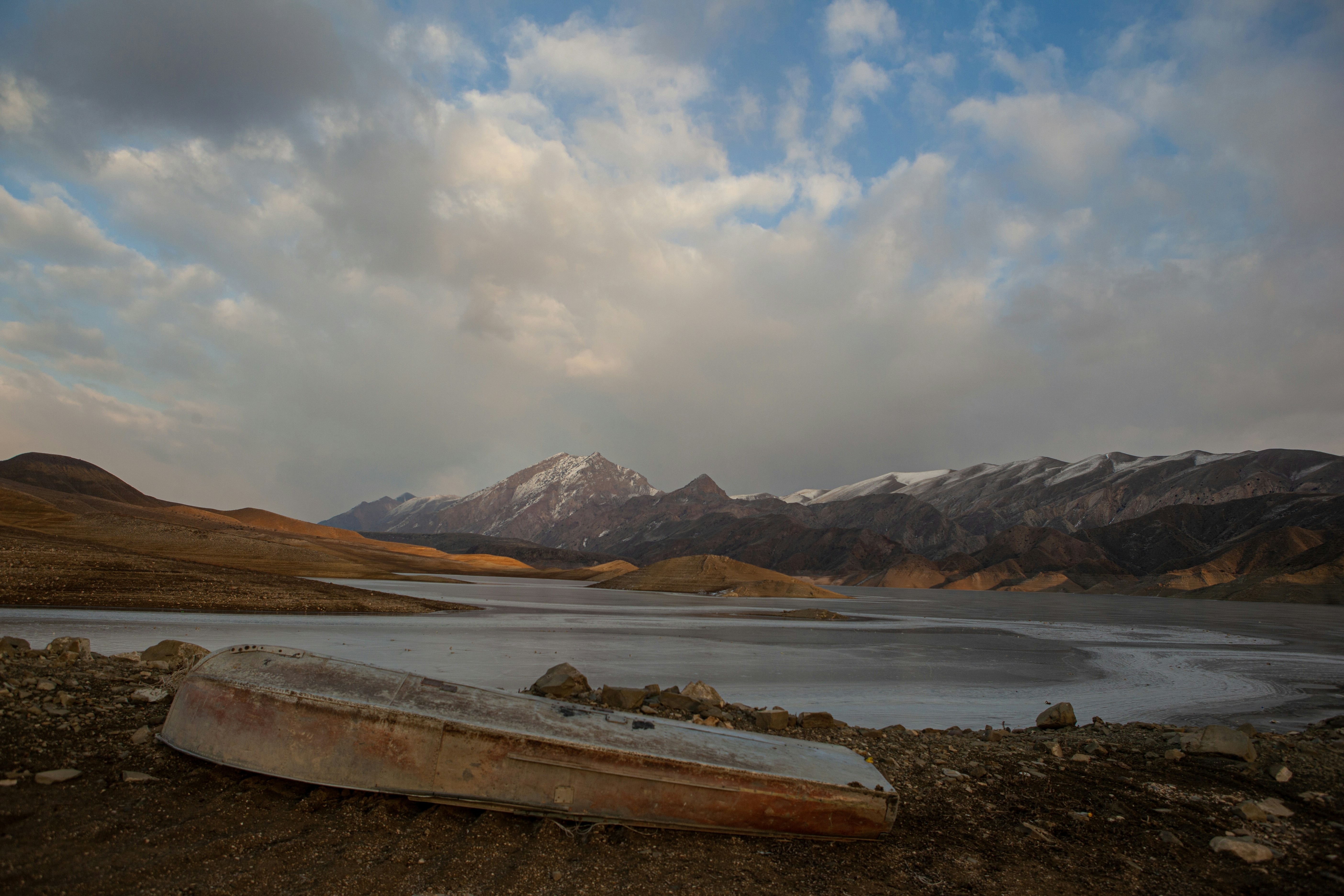 A boat sitting on top of a dirt field next to a lake photo – Free Lake ...