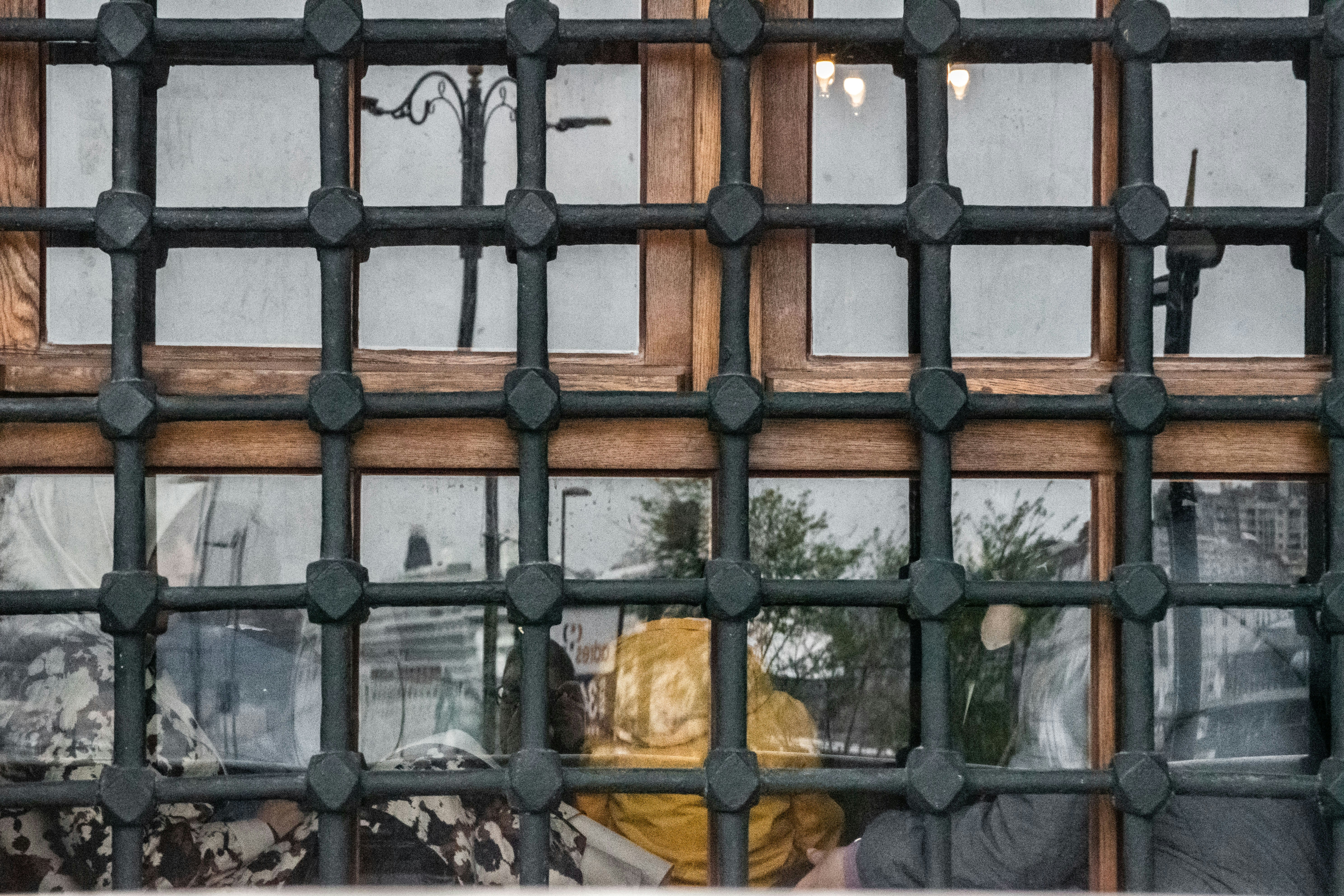 Yellow Figure Behind an Iron Grid: Window Reflections and Hidden Interior