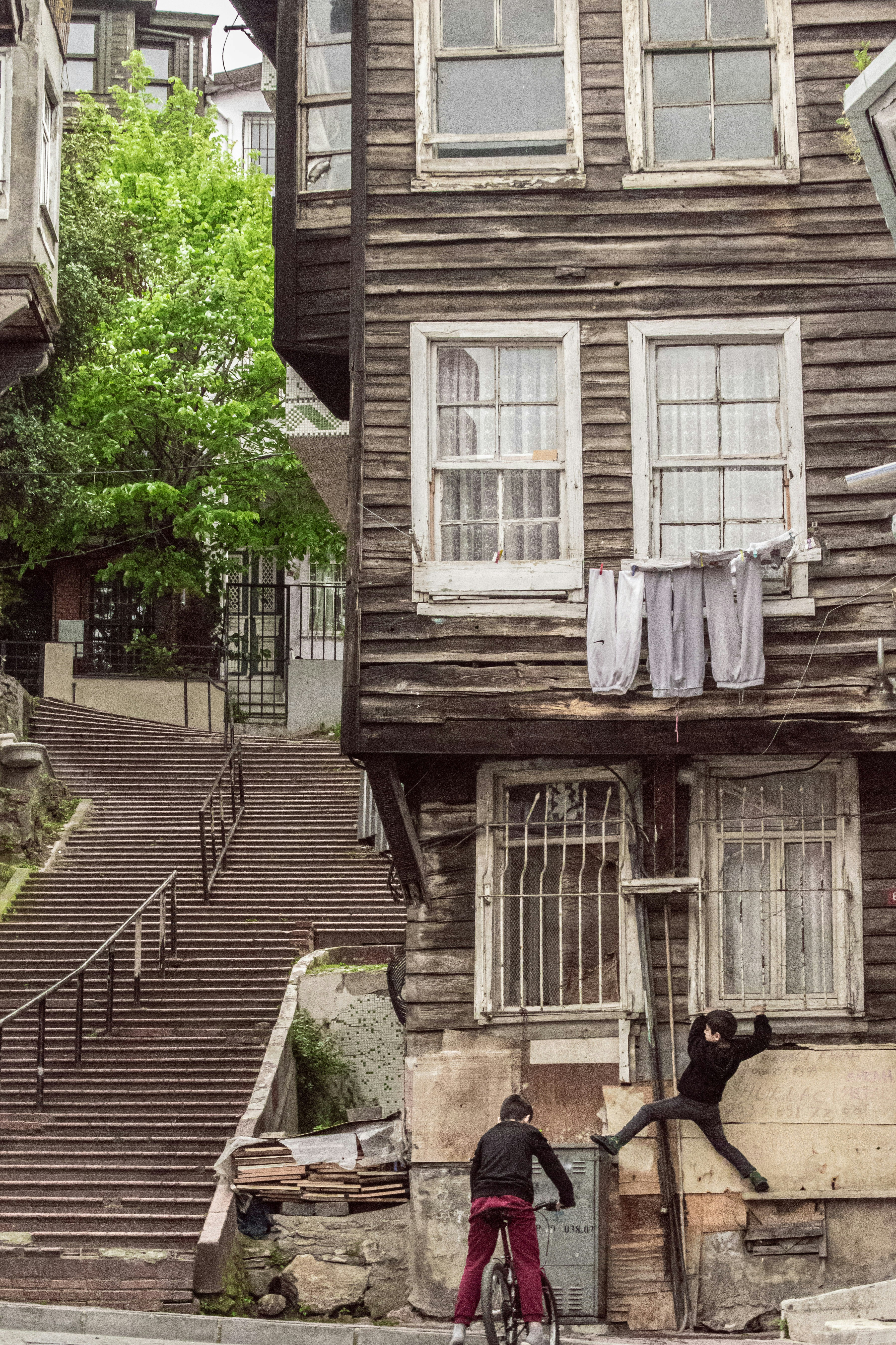 Climber on a Weathered Timber Facade: Quiet Drama by Laundry and Stairs