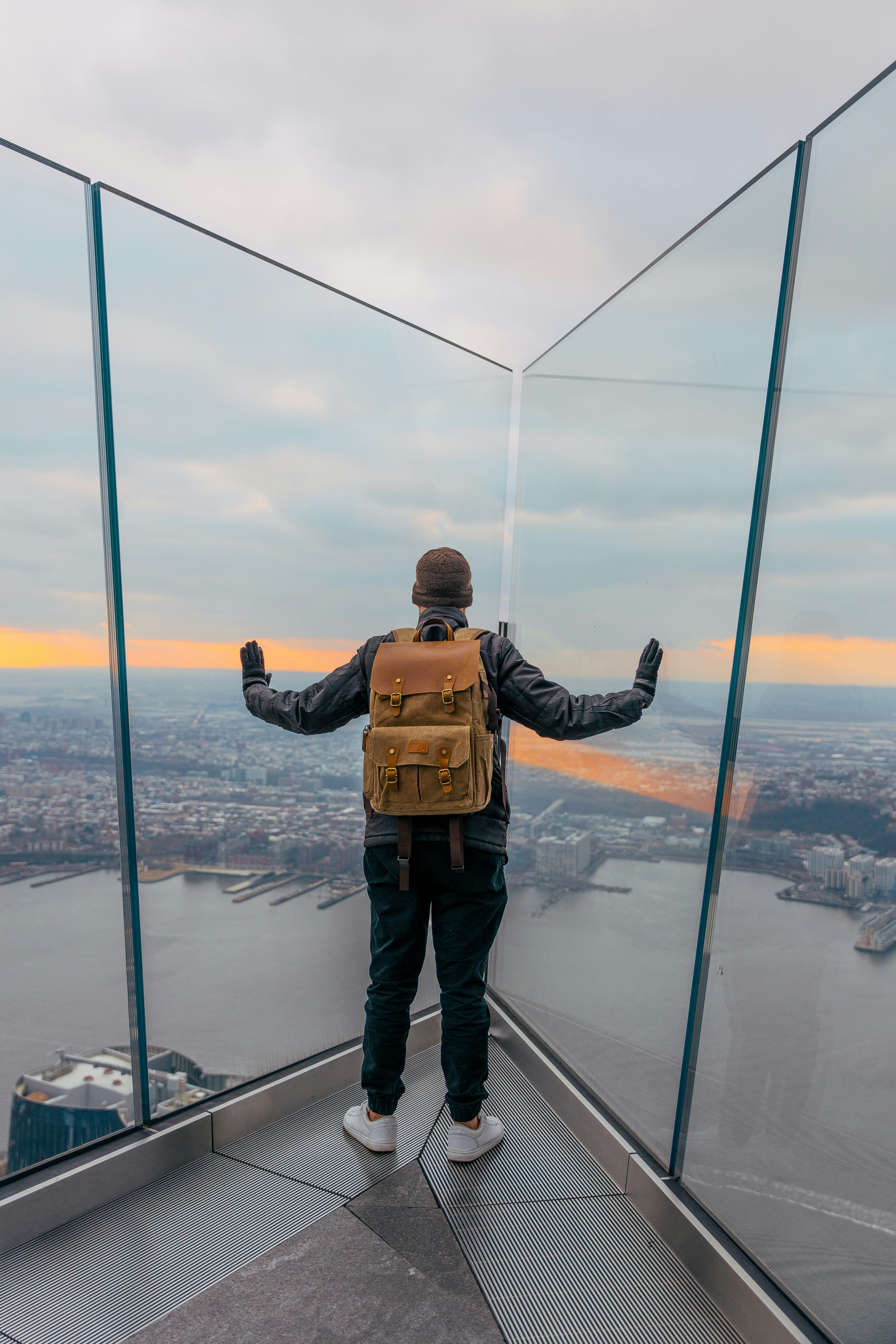 Edge of the City: Backpacker on a Glass Skywalk at Sunset