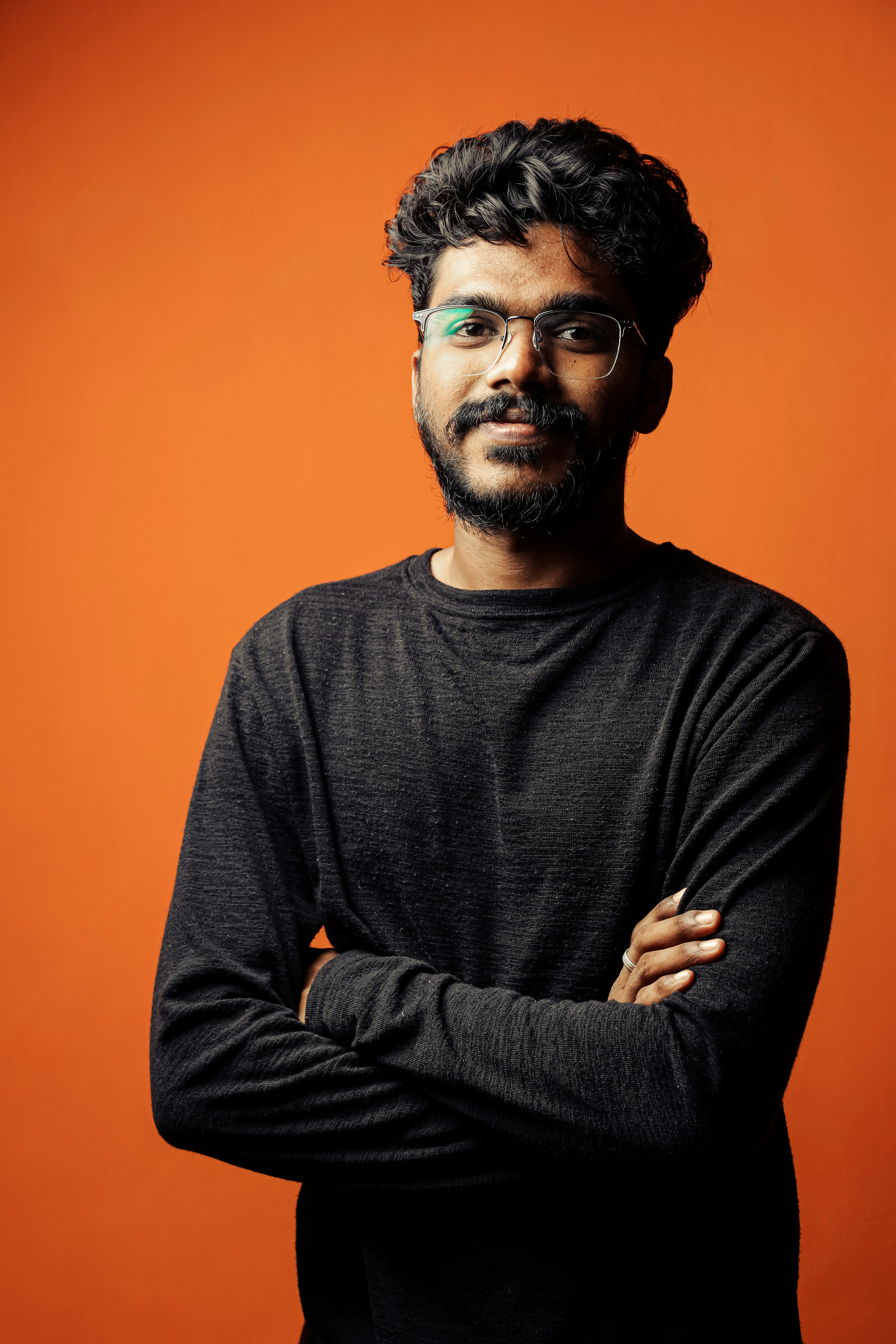 A man with a beard and glasses standing with his arms crossed photo ...
