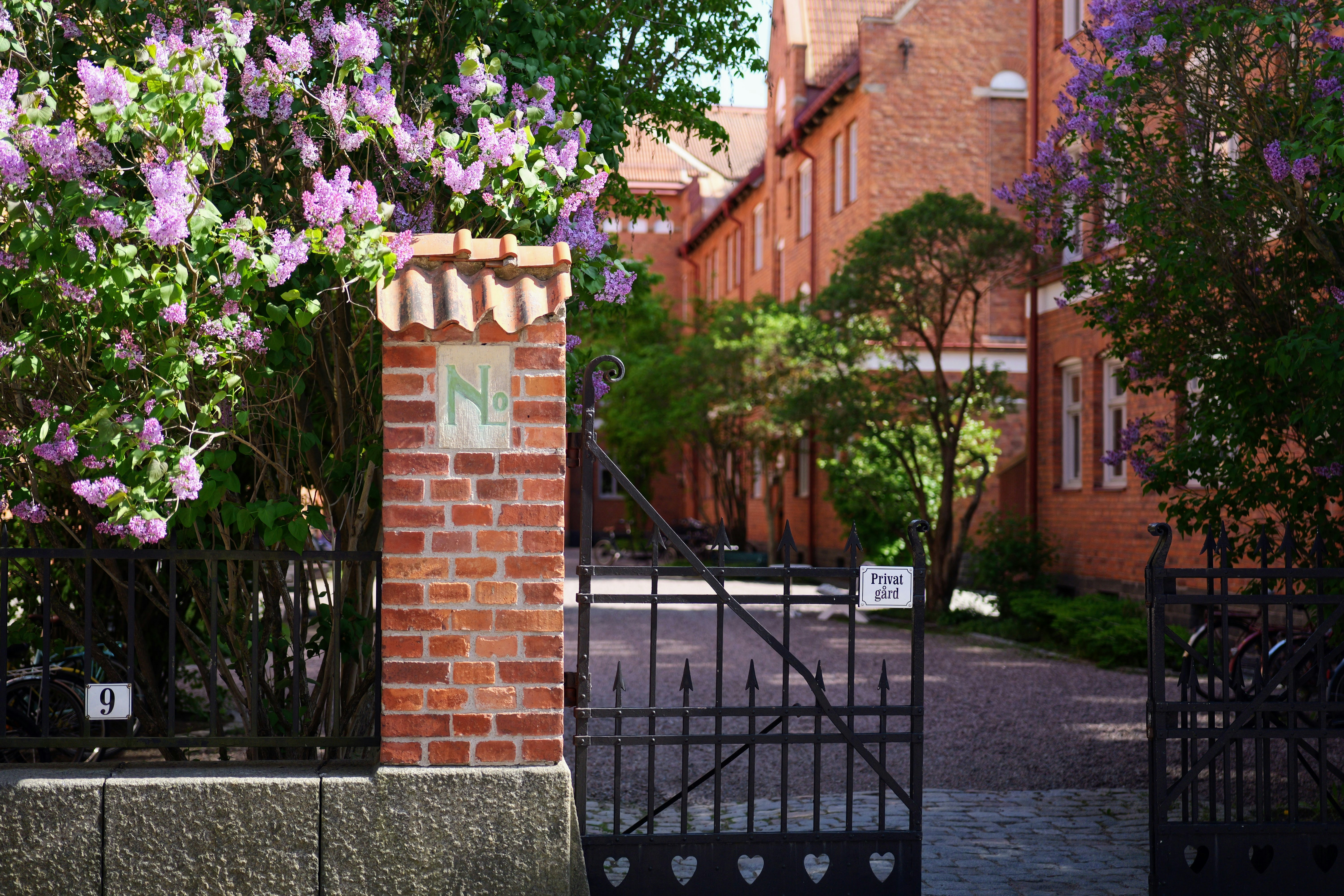 Un portail en brique avec un panneau devant un bâtiment en briques ...