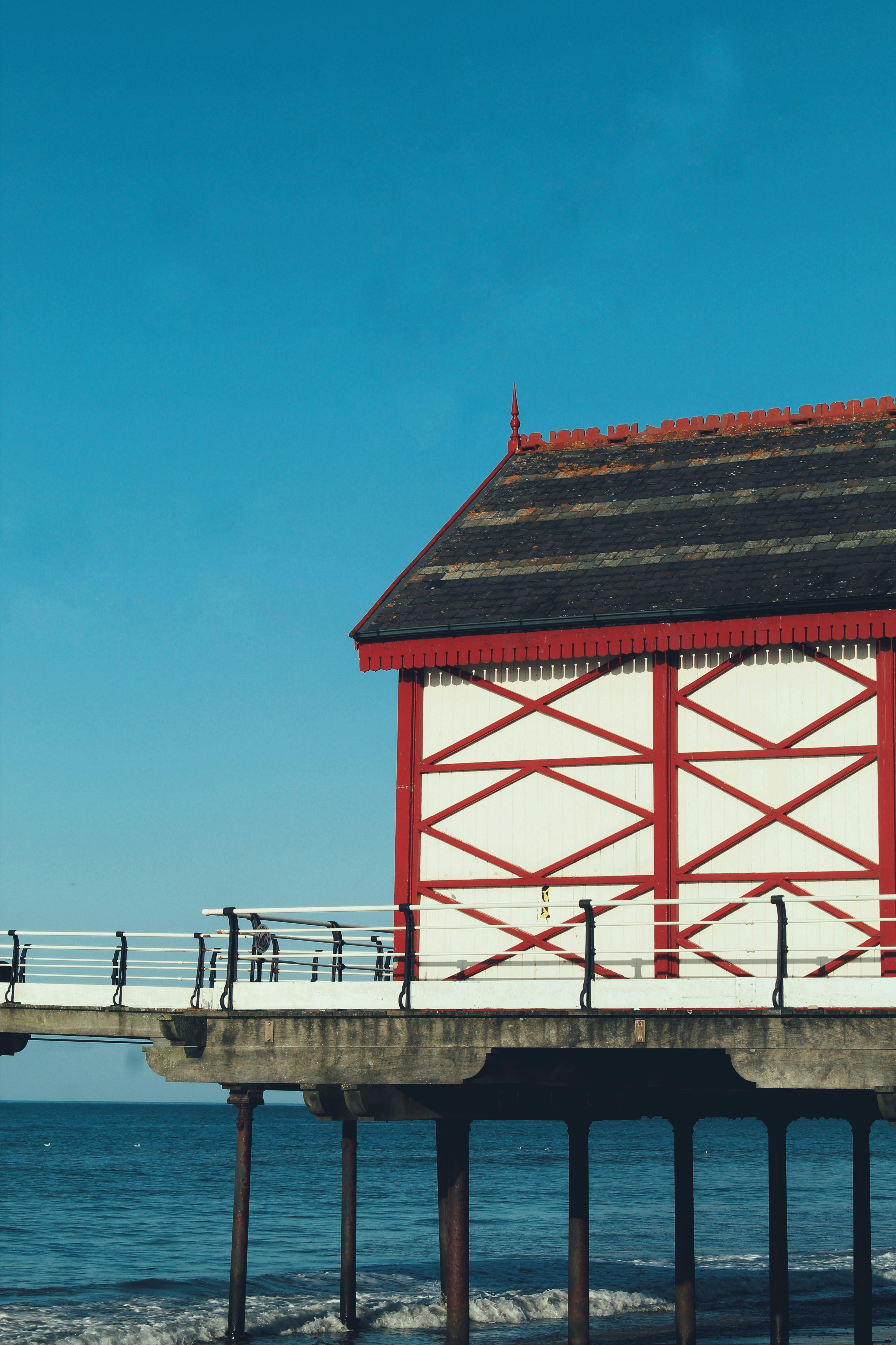Crimson Timberframe at Sea: A Pier Pavilion Reaches Toward a Clear Horizon