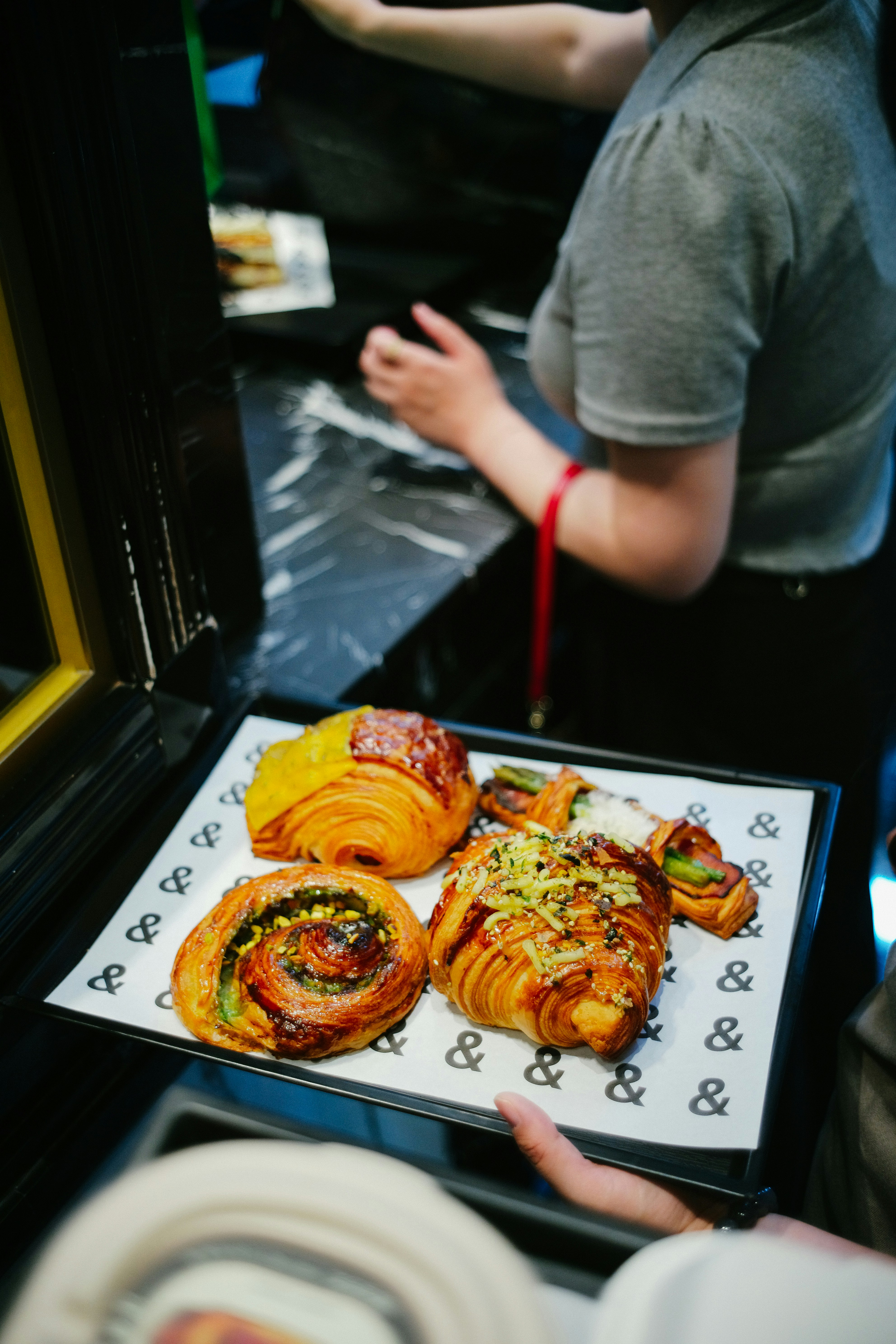 Spiral Pastries on a Paper-Lined Tray at a Busy Counter