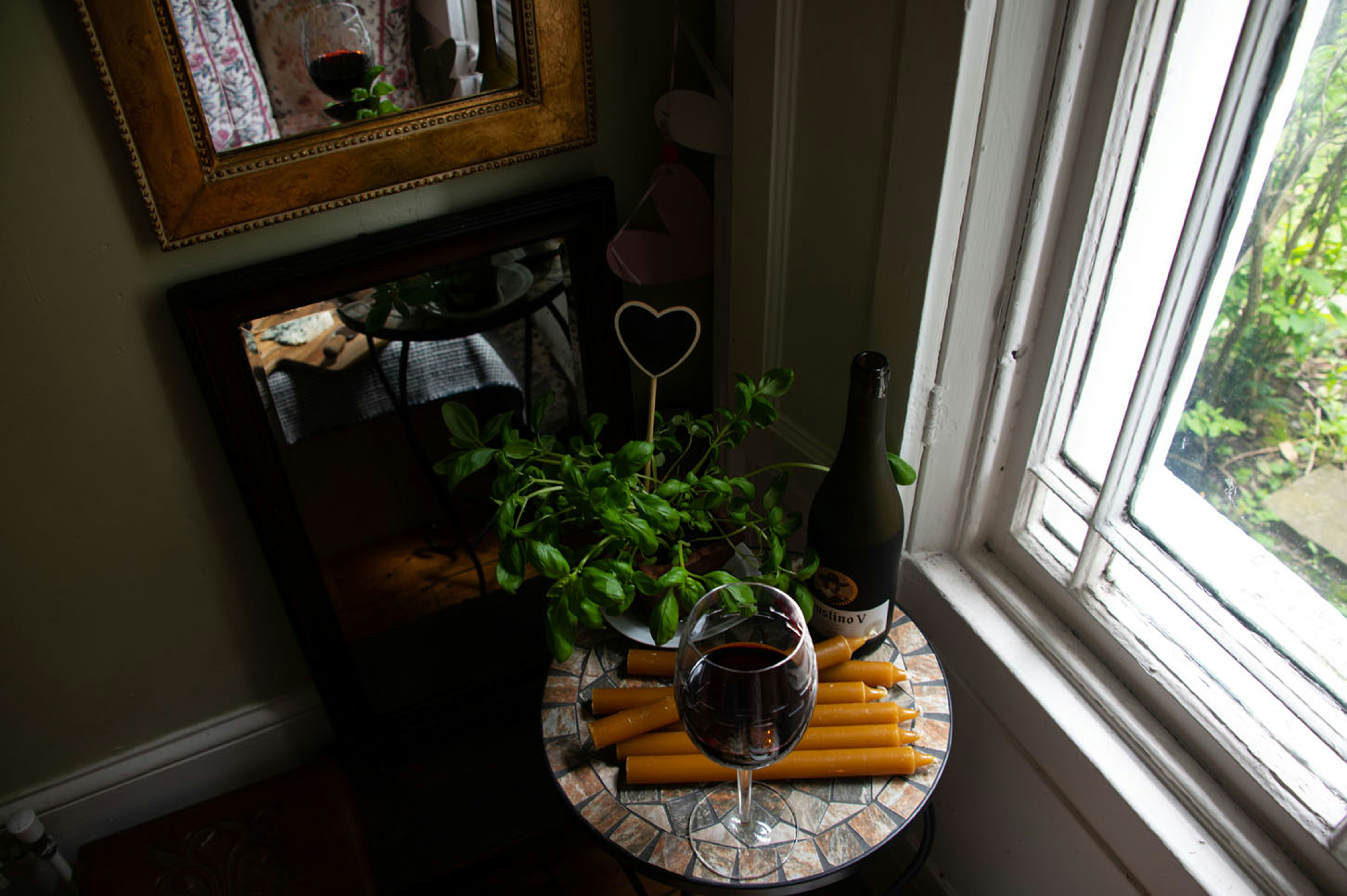 Sunlit Window Corner: Mosaic Table Still-Life with Wine, Candles, and Greenery