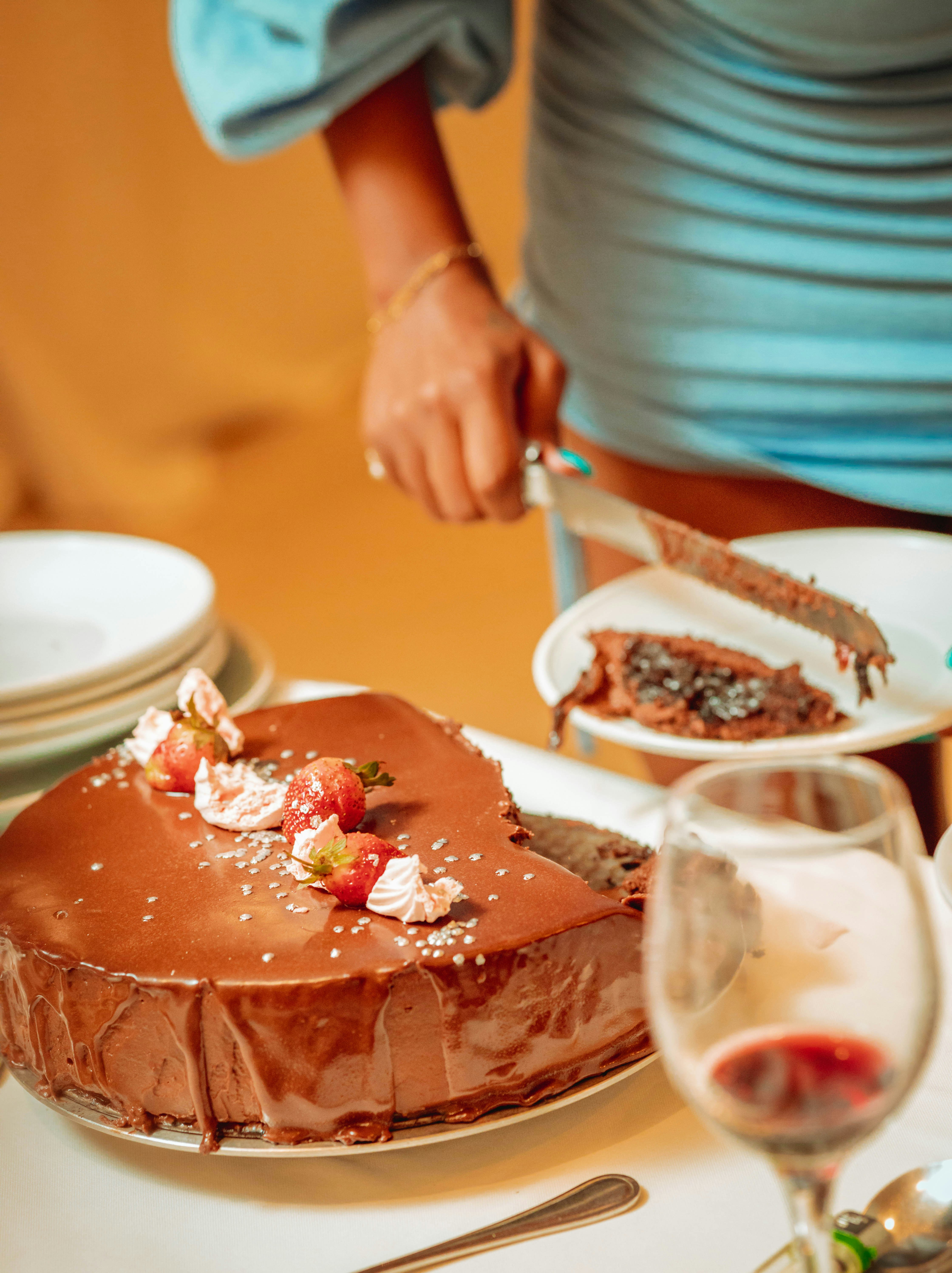 Velvety Chocolate Cake Under Warm Light as a Hand Carves the First Slice