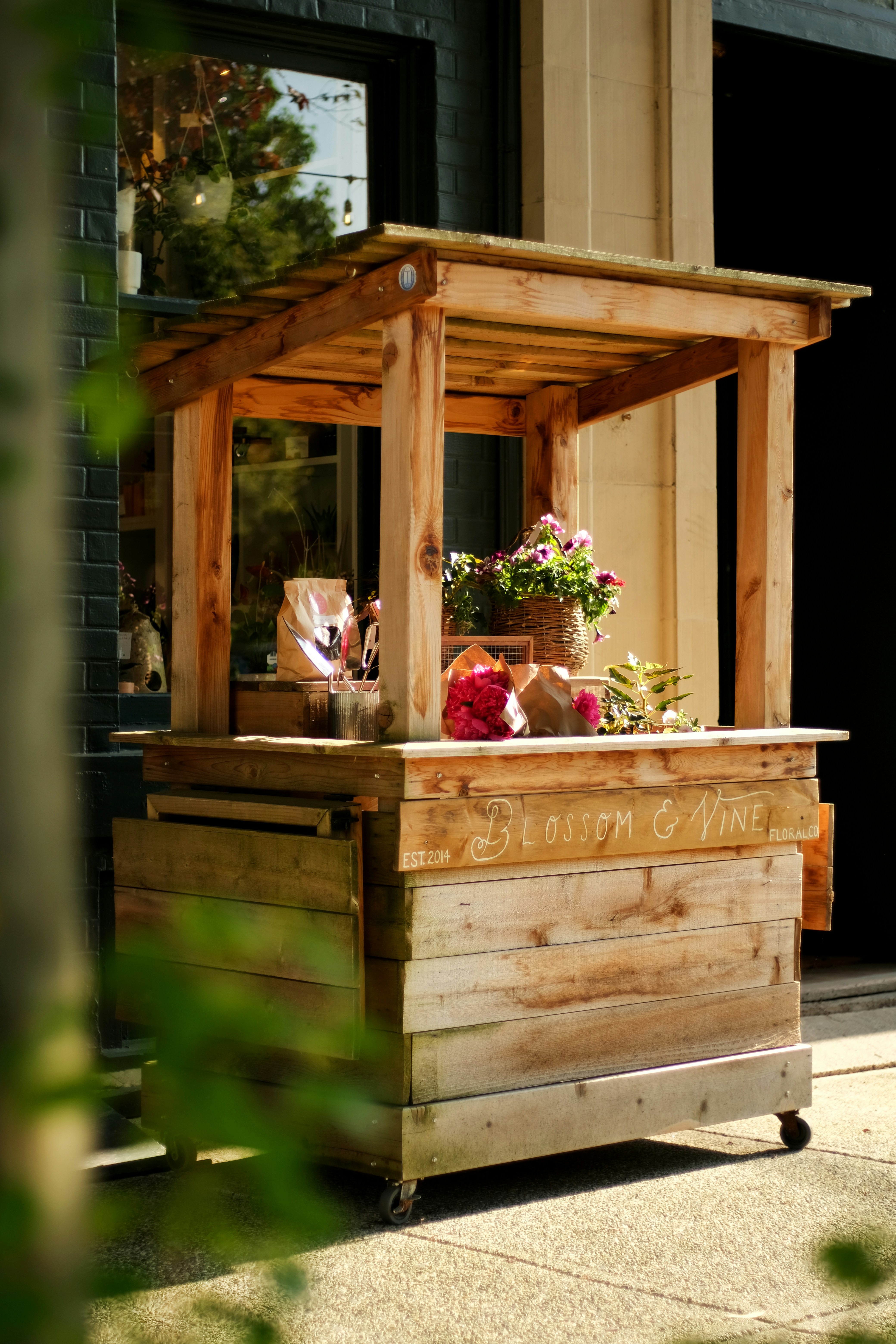 Sunlit Florist Stand: Blooms on a Weathered Wooden Cart