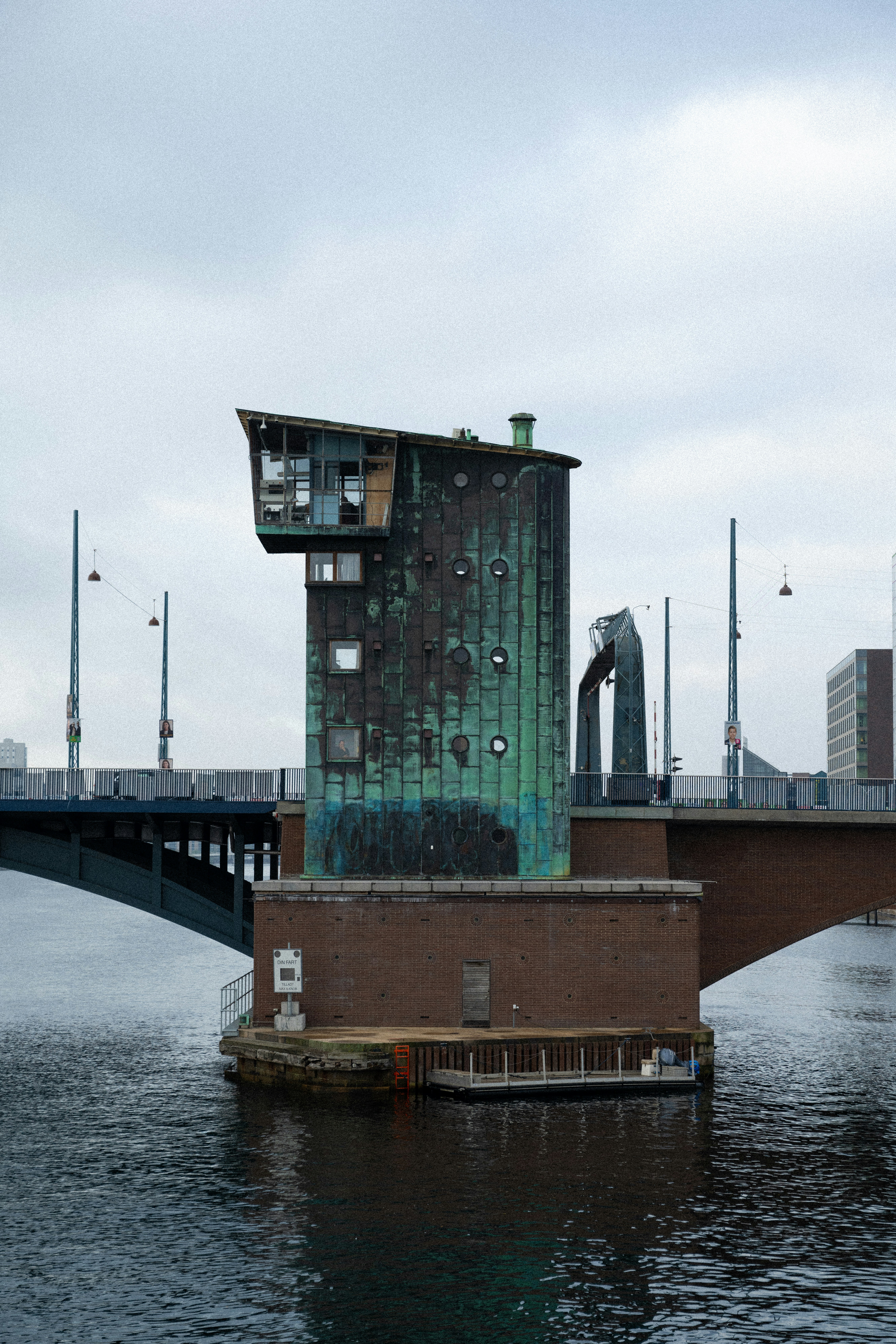 The Green Sentinel: Patina-Tinted Tower Beside a City Bridge