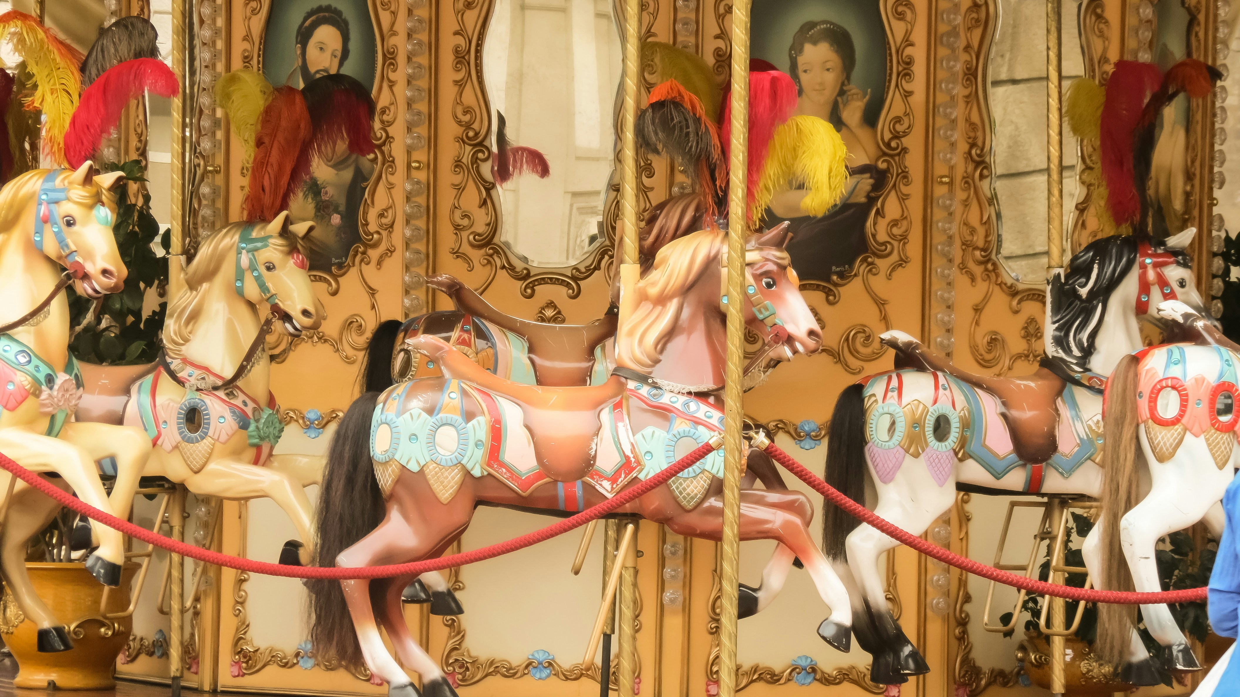 Ornately decorated horses on a vintage carousel with intricate painted panels.