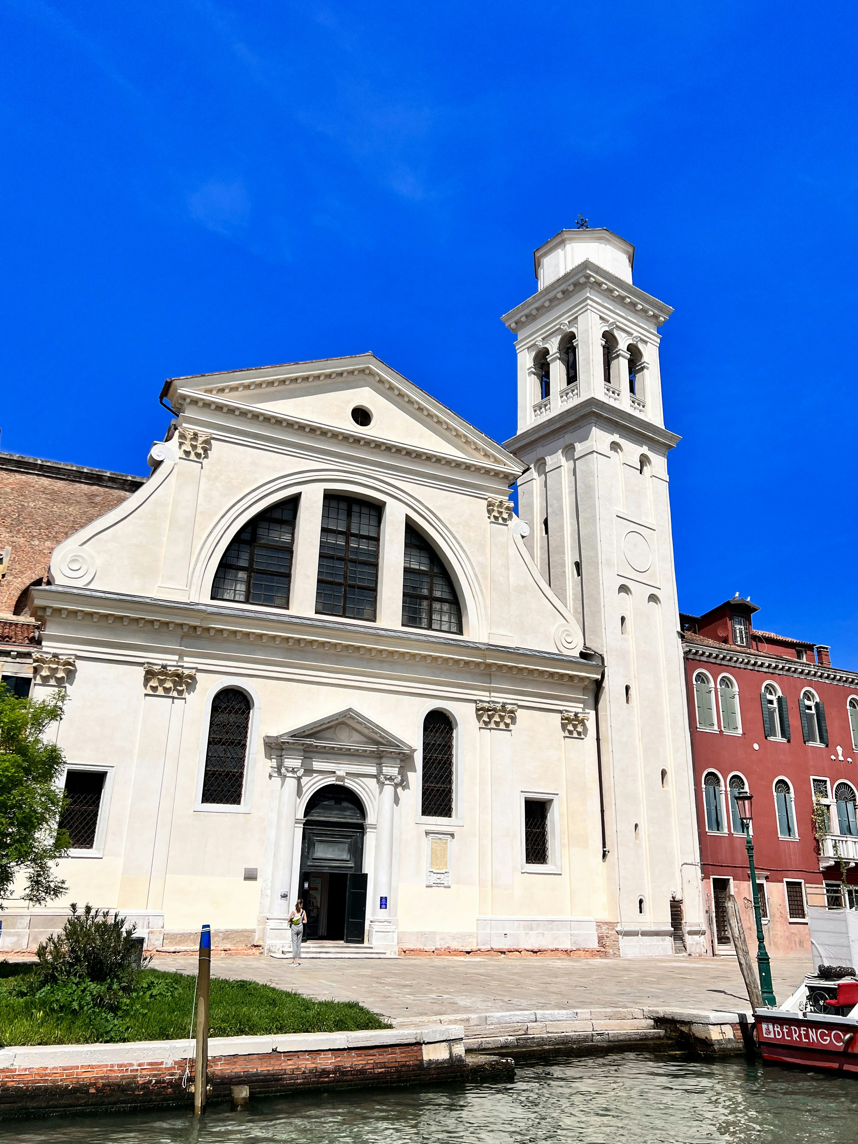 Sunlit Facade and Bell Tower Rising Over a Canal