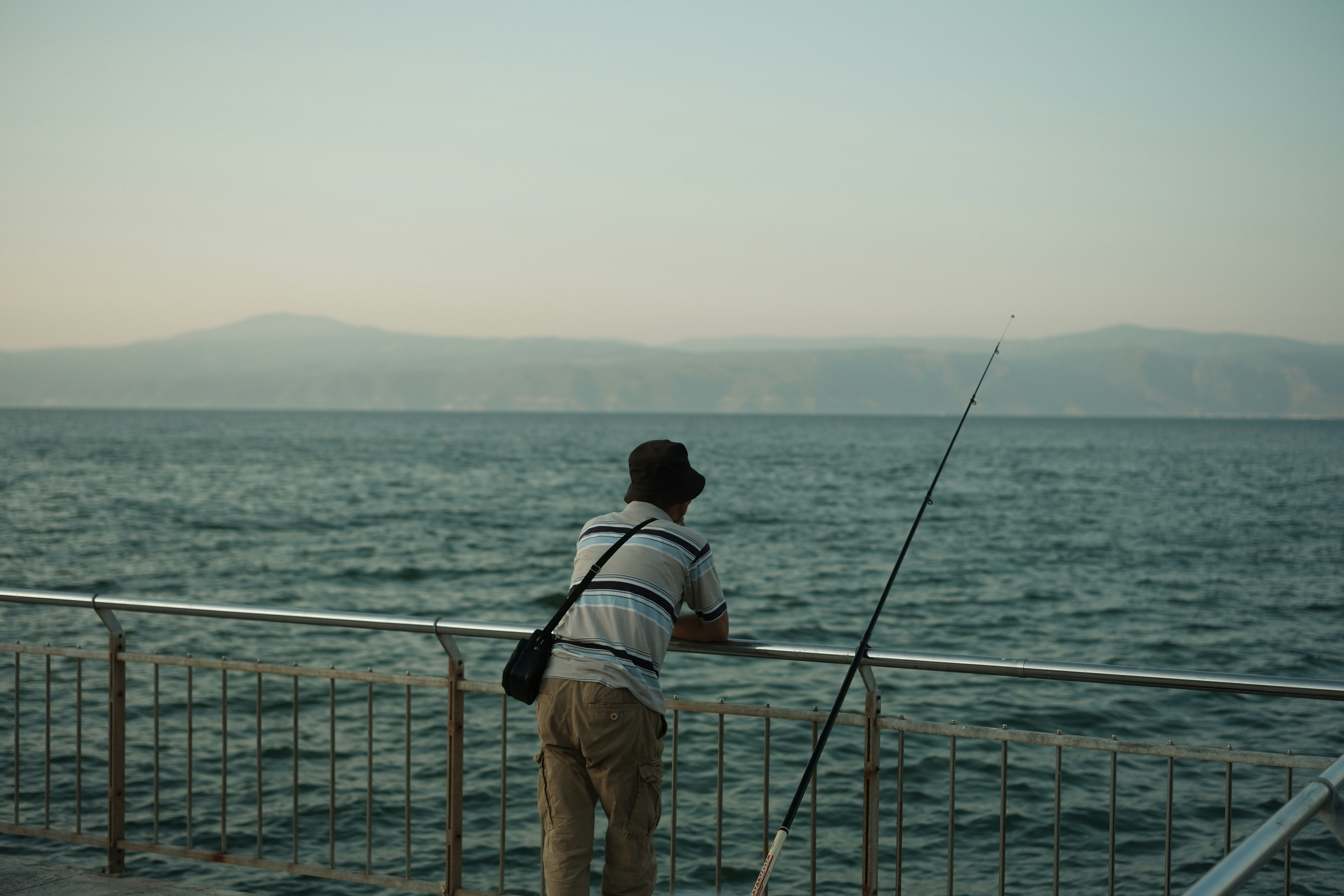 Foto Un hombre parado en un muelle sosteniendo una caña de pescar ...