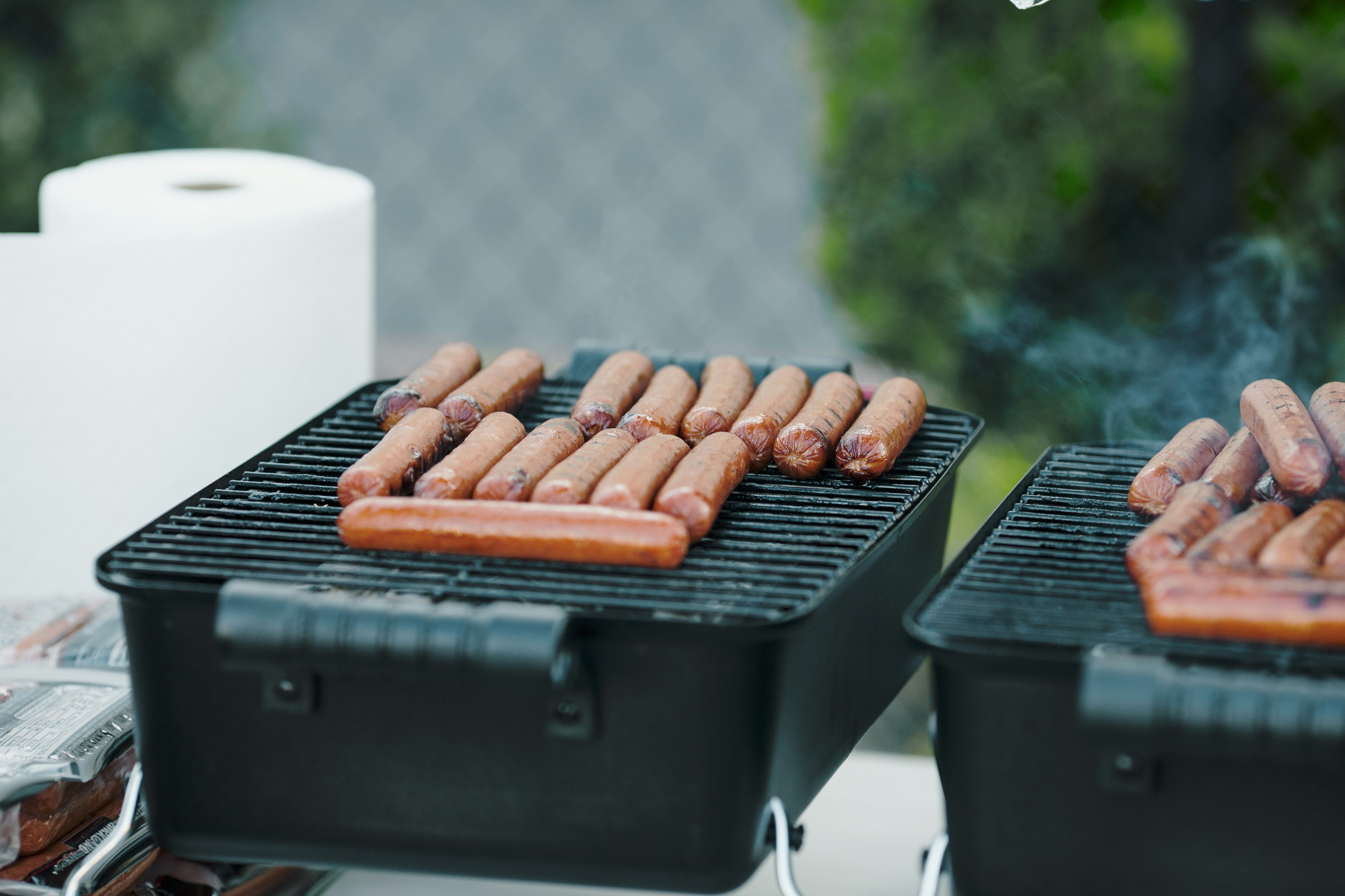 Sizzling Row: Sausages Toasting on Dual Grills in a Quiet Backyard
