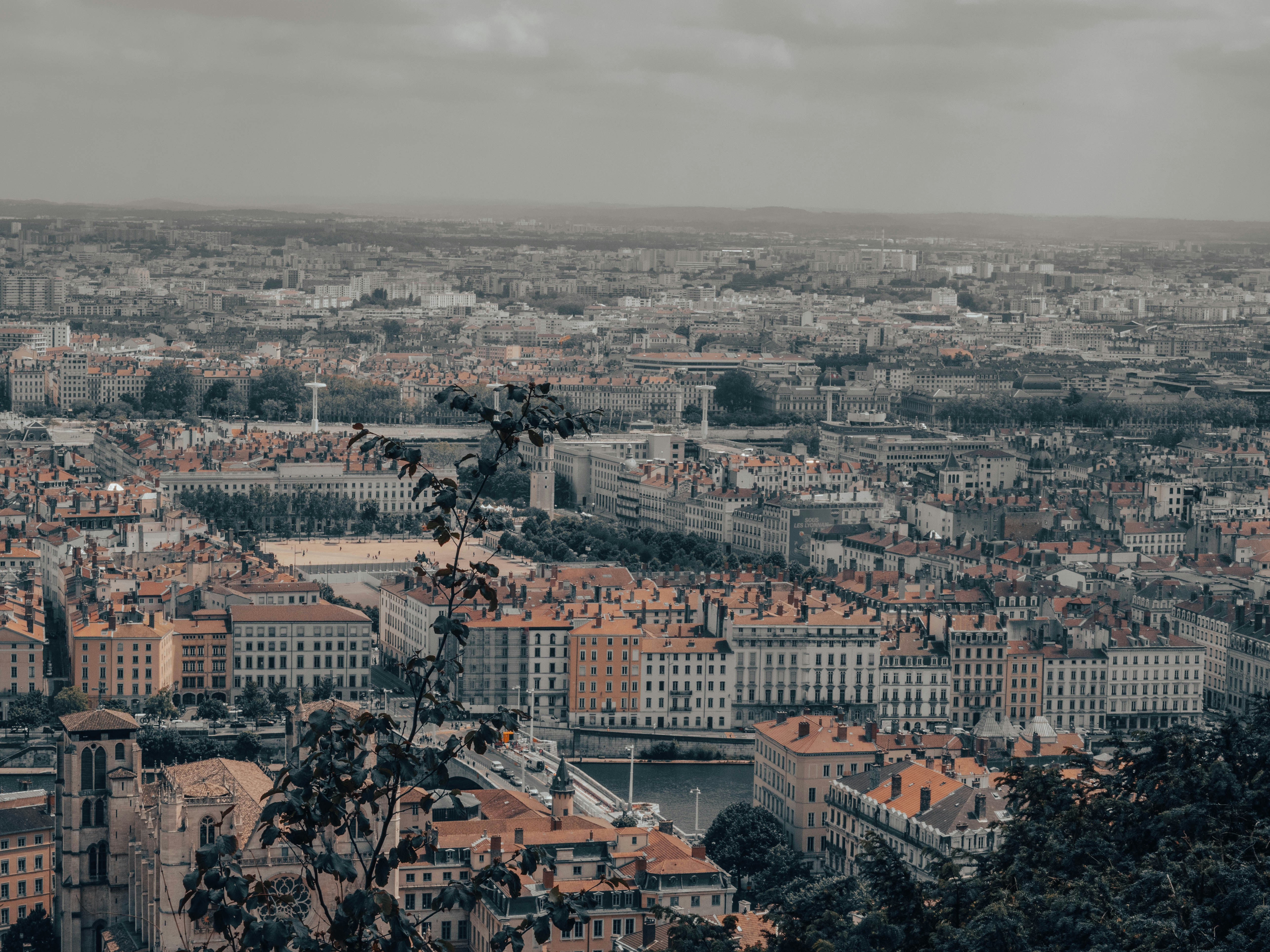 Expansive view of a historic city with dense architecture and winding river under a cloudy sky.