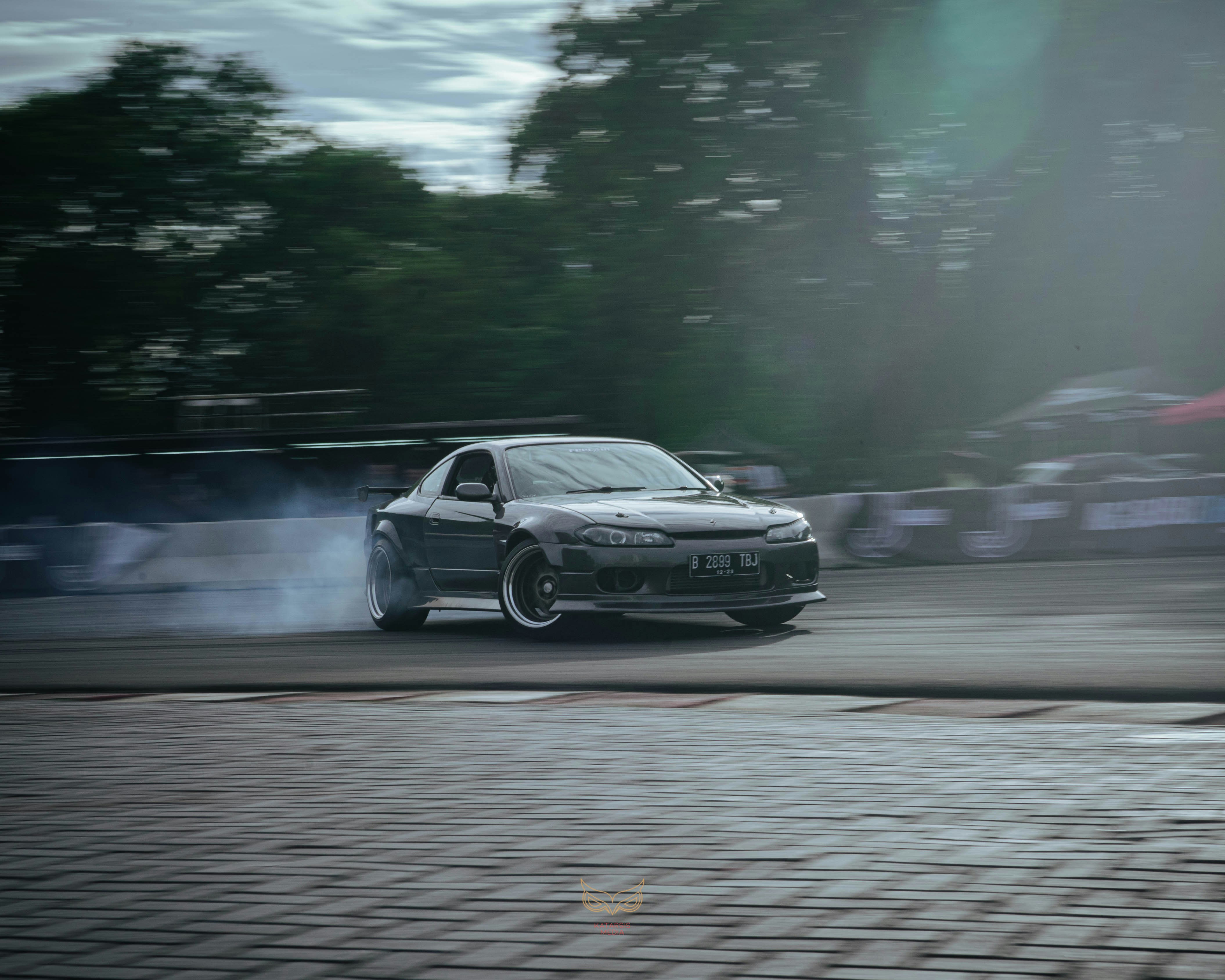 A car driving down a street with smoke coming out of it photo – Free ...