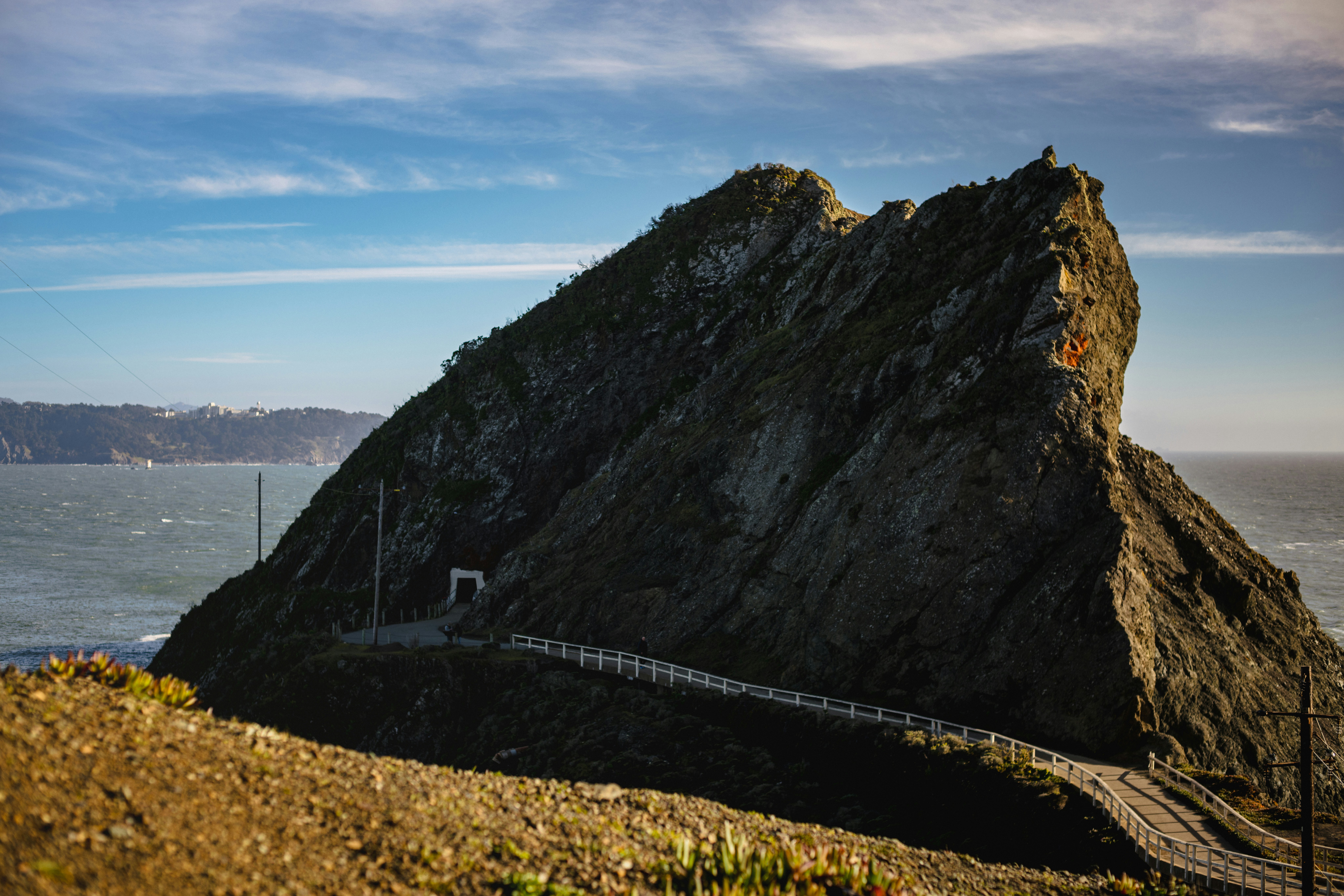 A large rock on the side of a road next to the ocean photo – Free Rock ...