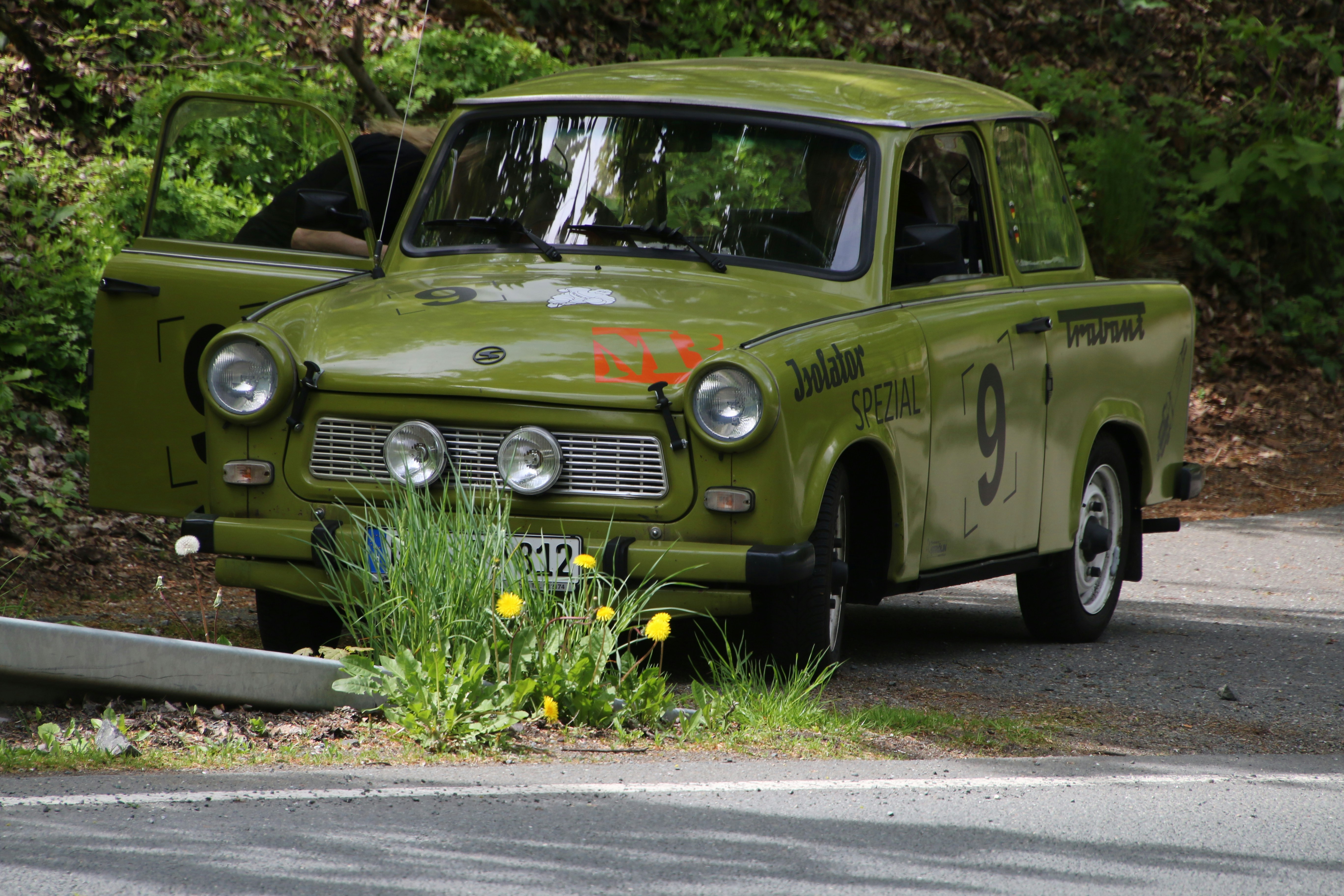 Olive Rally-Style Pickup Paused by a Sunlit Forest Road