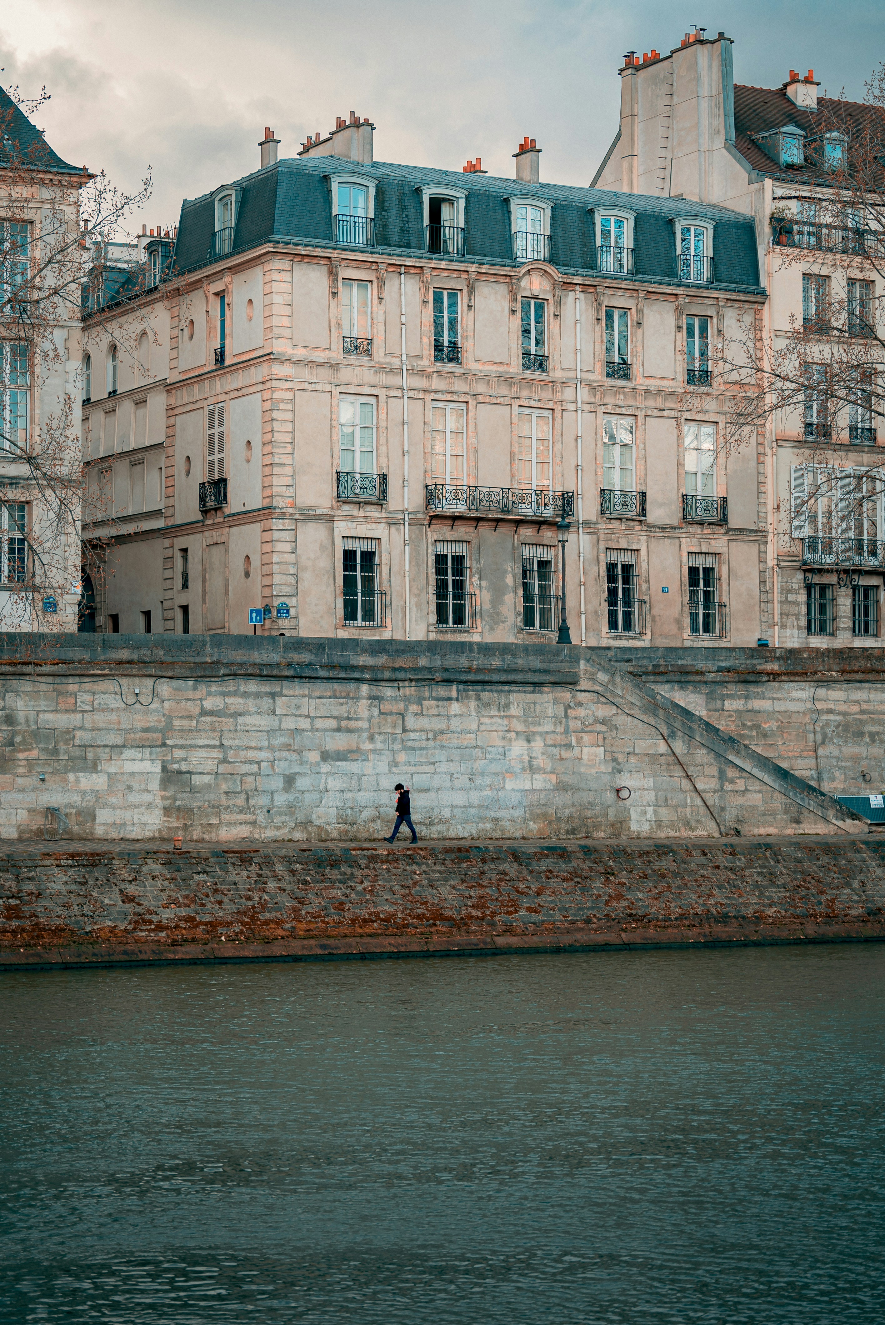Footsteps Along a Parisian Riverbank Beneath a Stately Facade