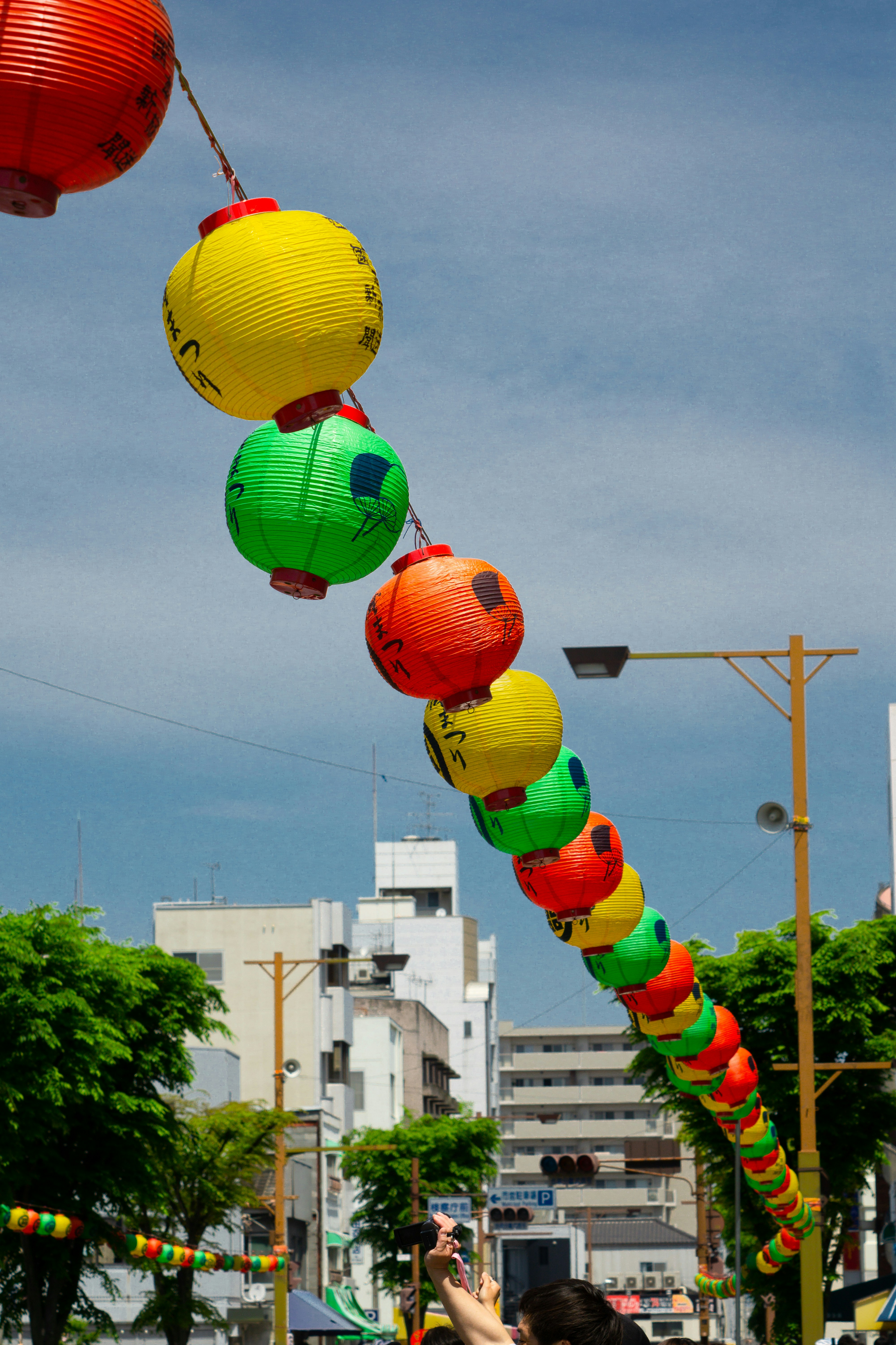 Colorful Lantern Colonnade Above a Sunlit City Street