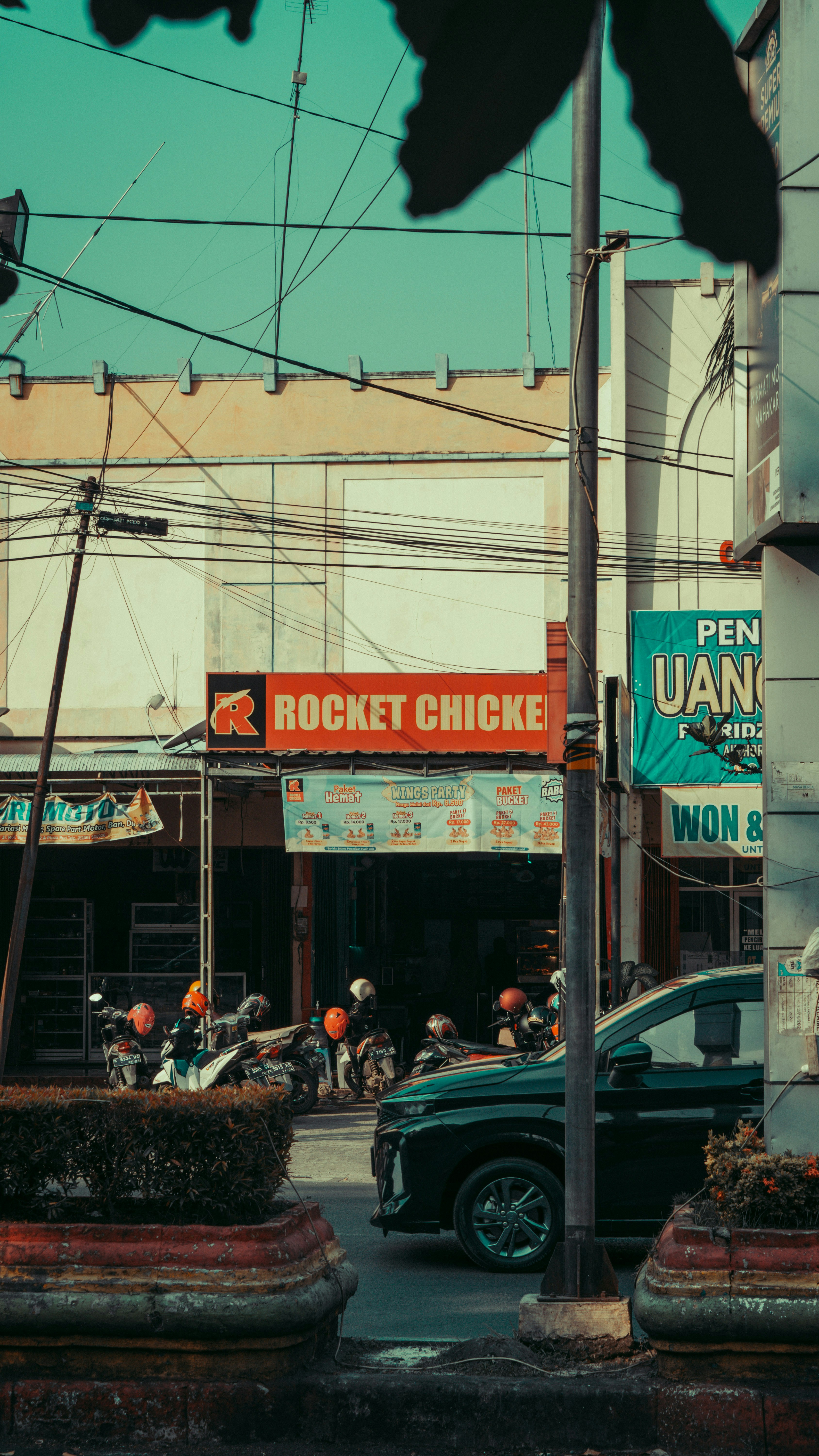 A street corner with cars and motorcycles parked on the side of the ...
