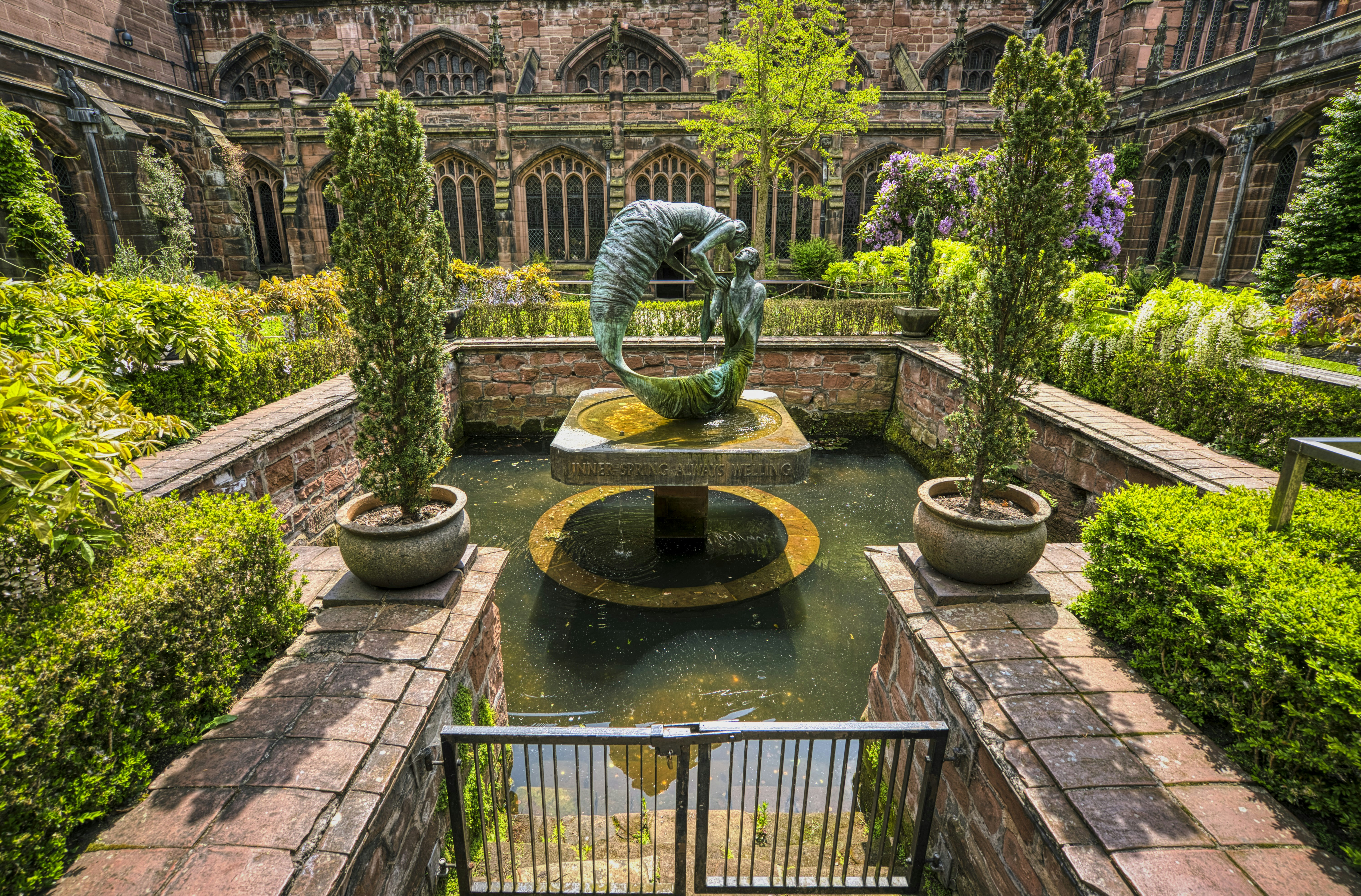 Hydro Ring in the Cloister Garden: Bronze sculpture framed by water and ivy
