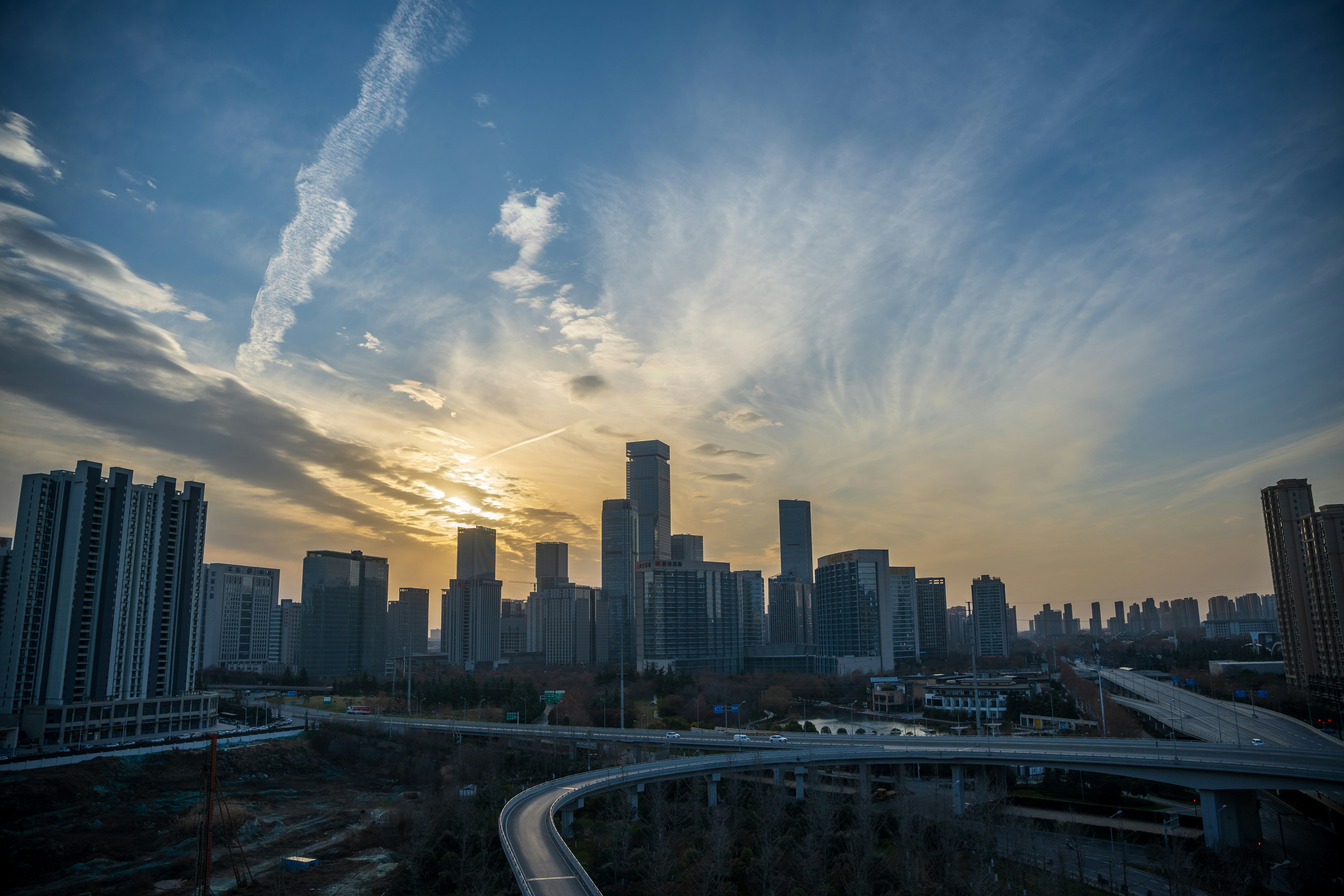 City skyline with towering buildings silhouetted against a dramatic sunset sky.