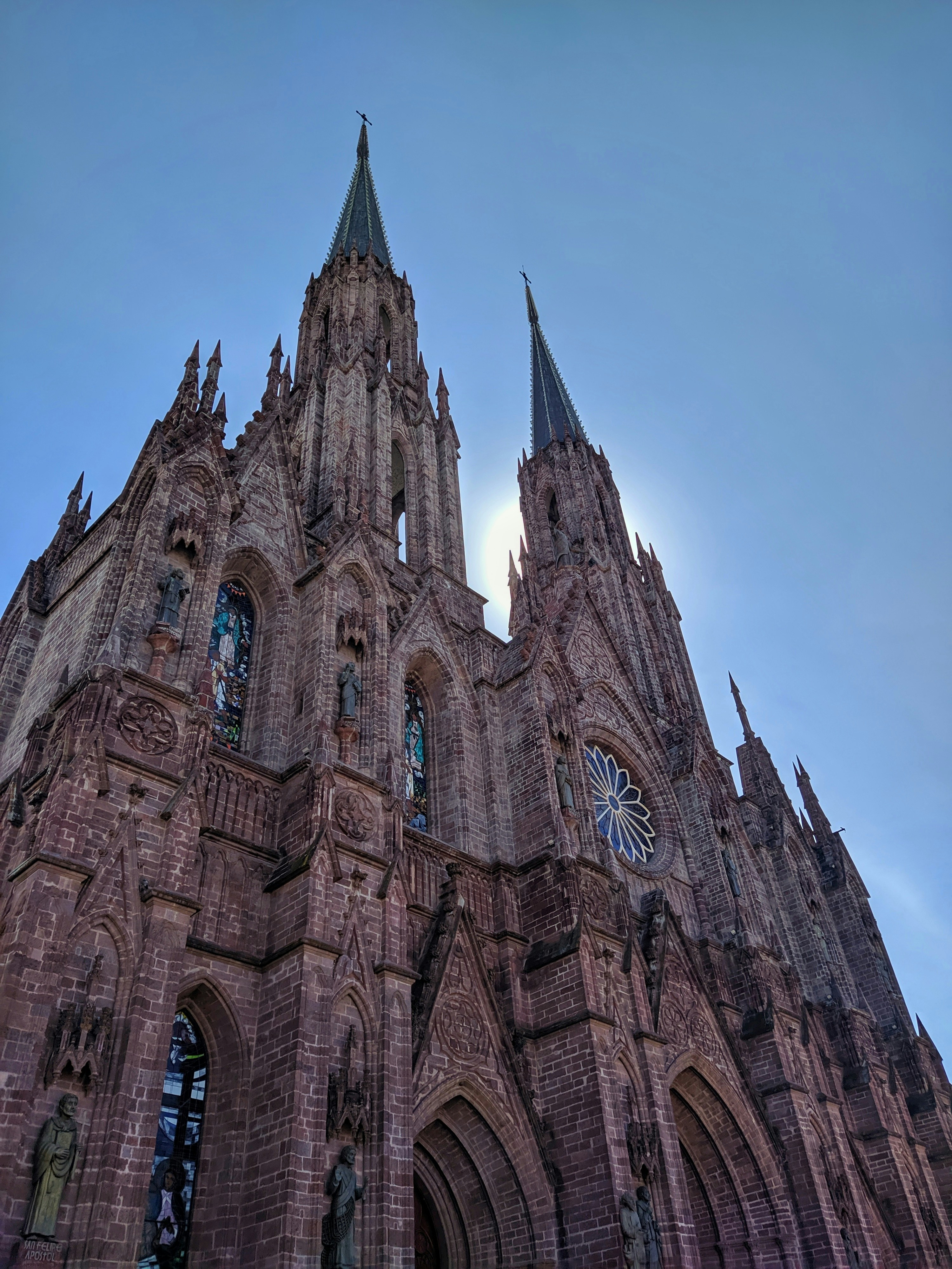 Majestic Gothic cathedral with intricate stonework and stained glass, illuminated by the sun from behind.