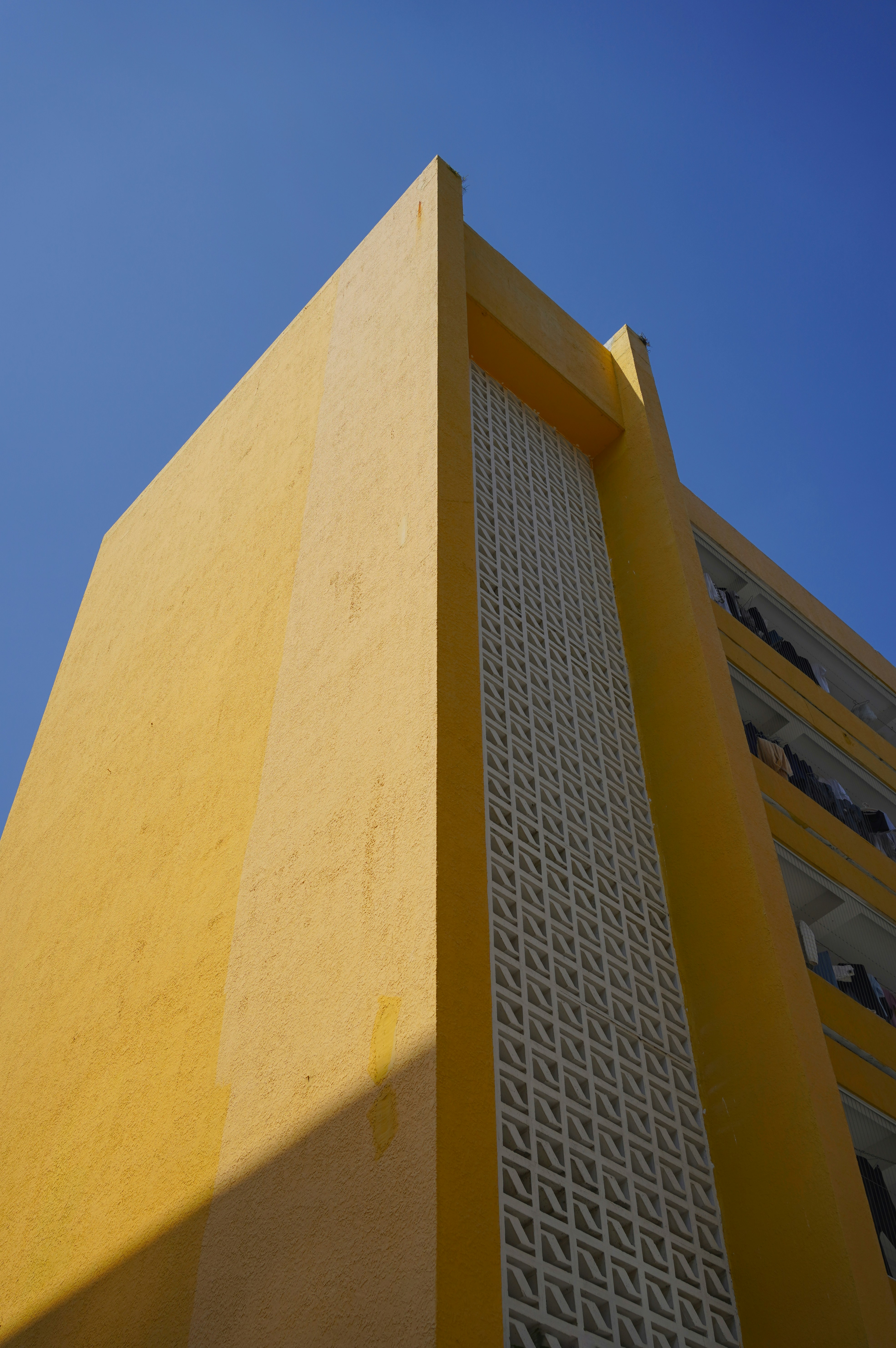 A tall yellow building with a blue sky in the background photo – Free ...