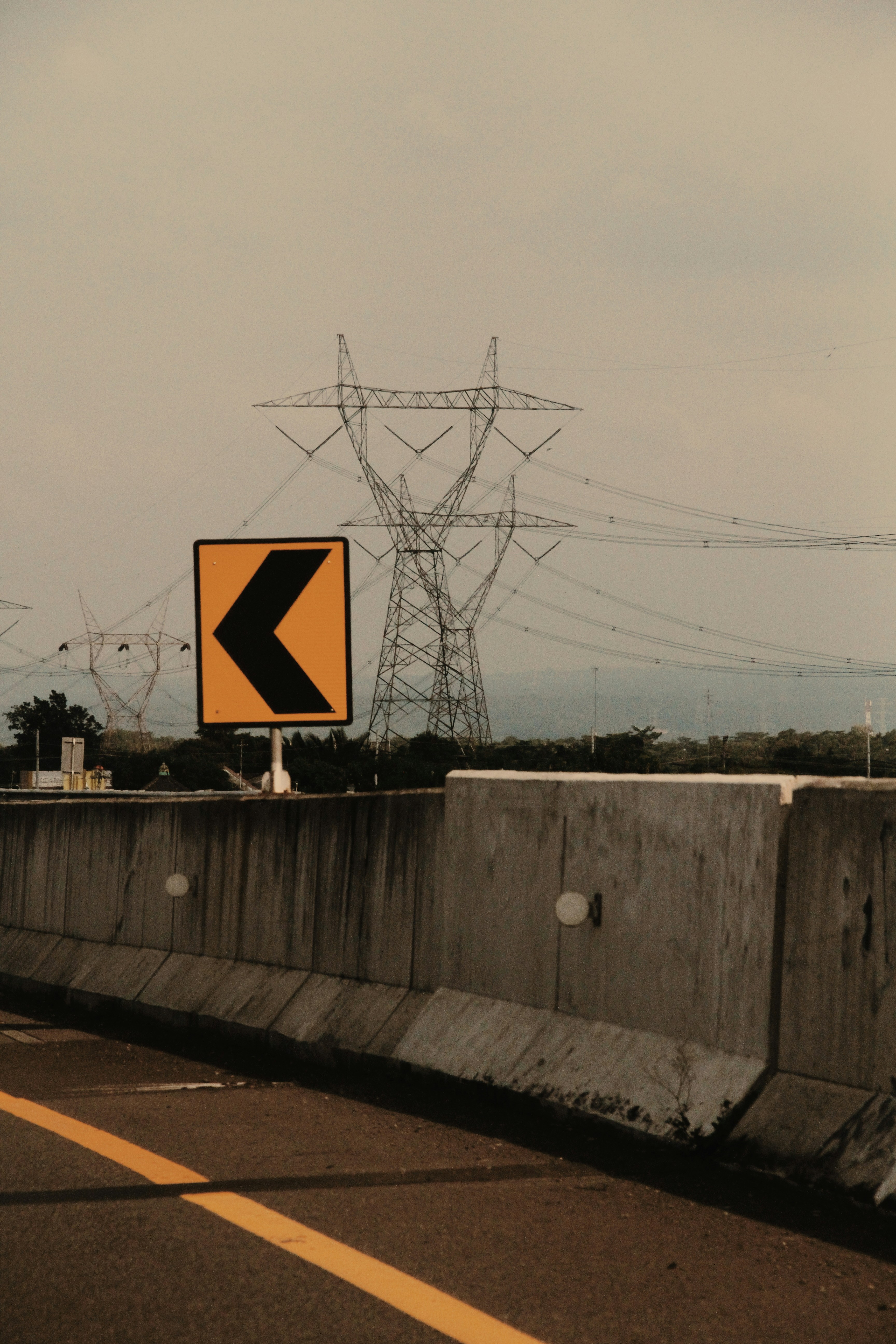 Leftward Signal: A Lonesome Highway Chevron Beneath Power Lines at Dusk