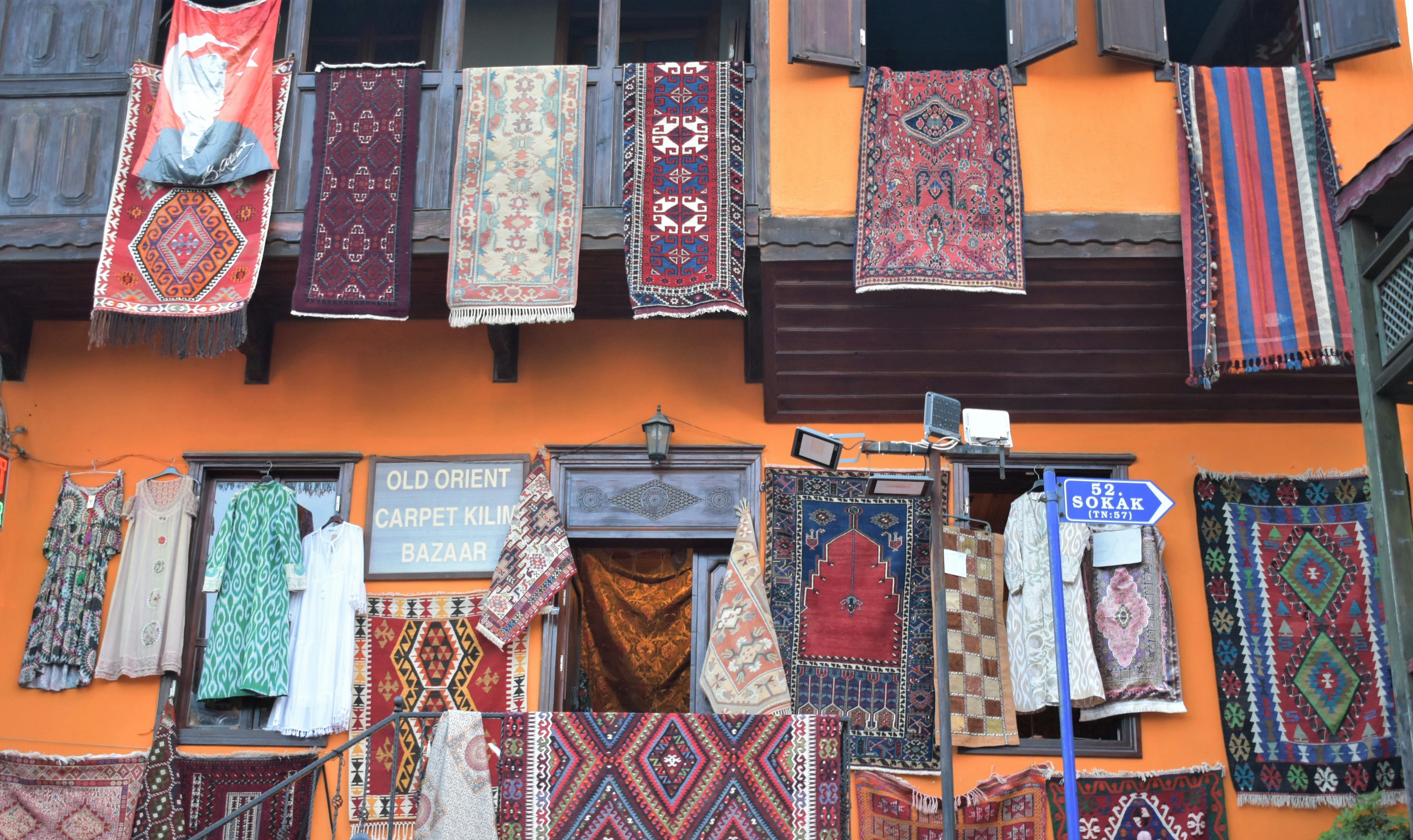 A building with a bunch of colorful rugs hanging from the side of it ...
