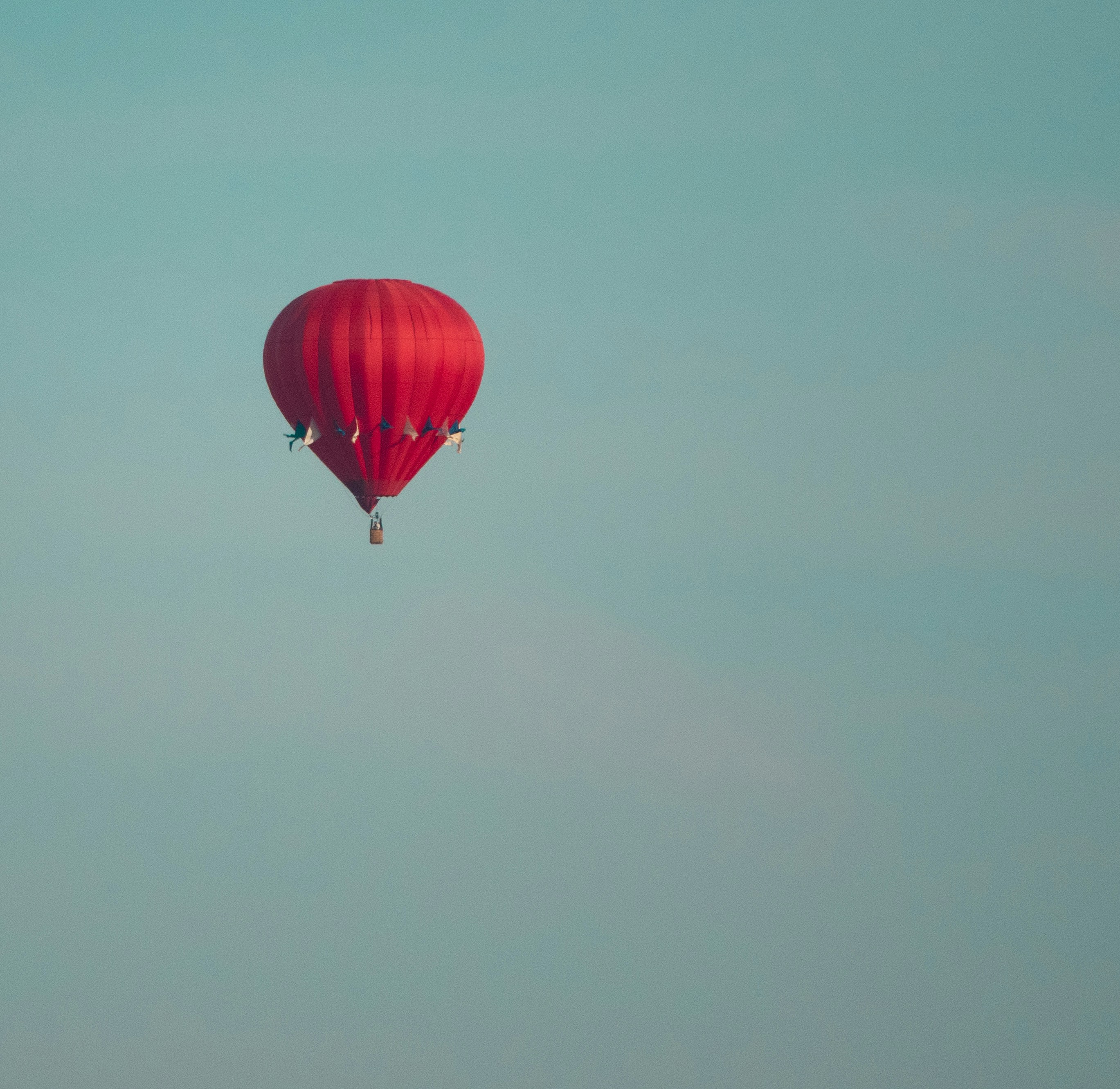 Crimson Balloon Drifts Over a Quiet Blue Expanse
