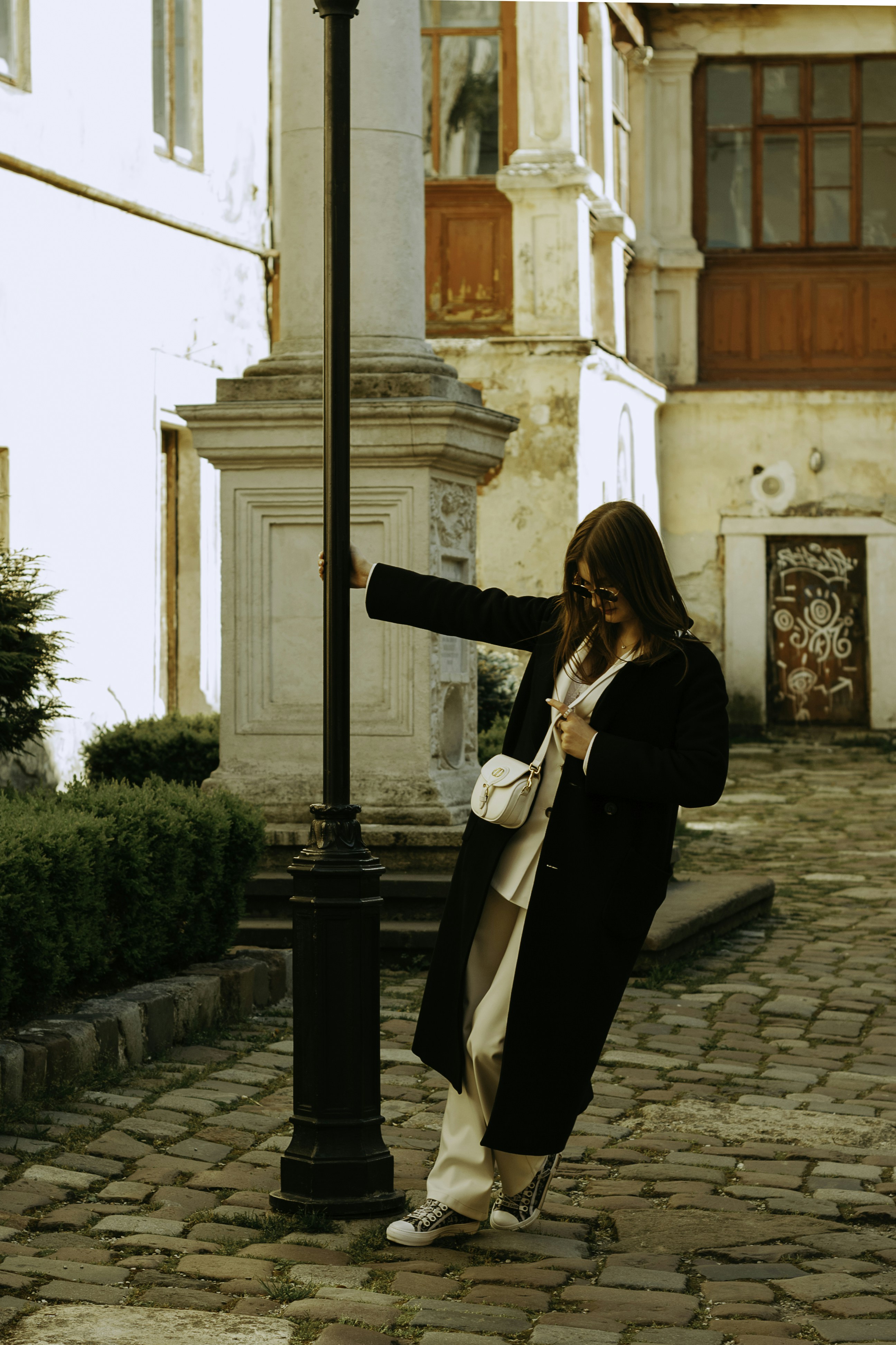 A woman leaning against a lamp post on a cobblestone street photo ...